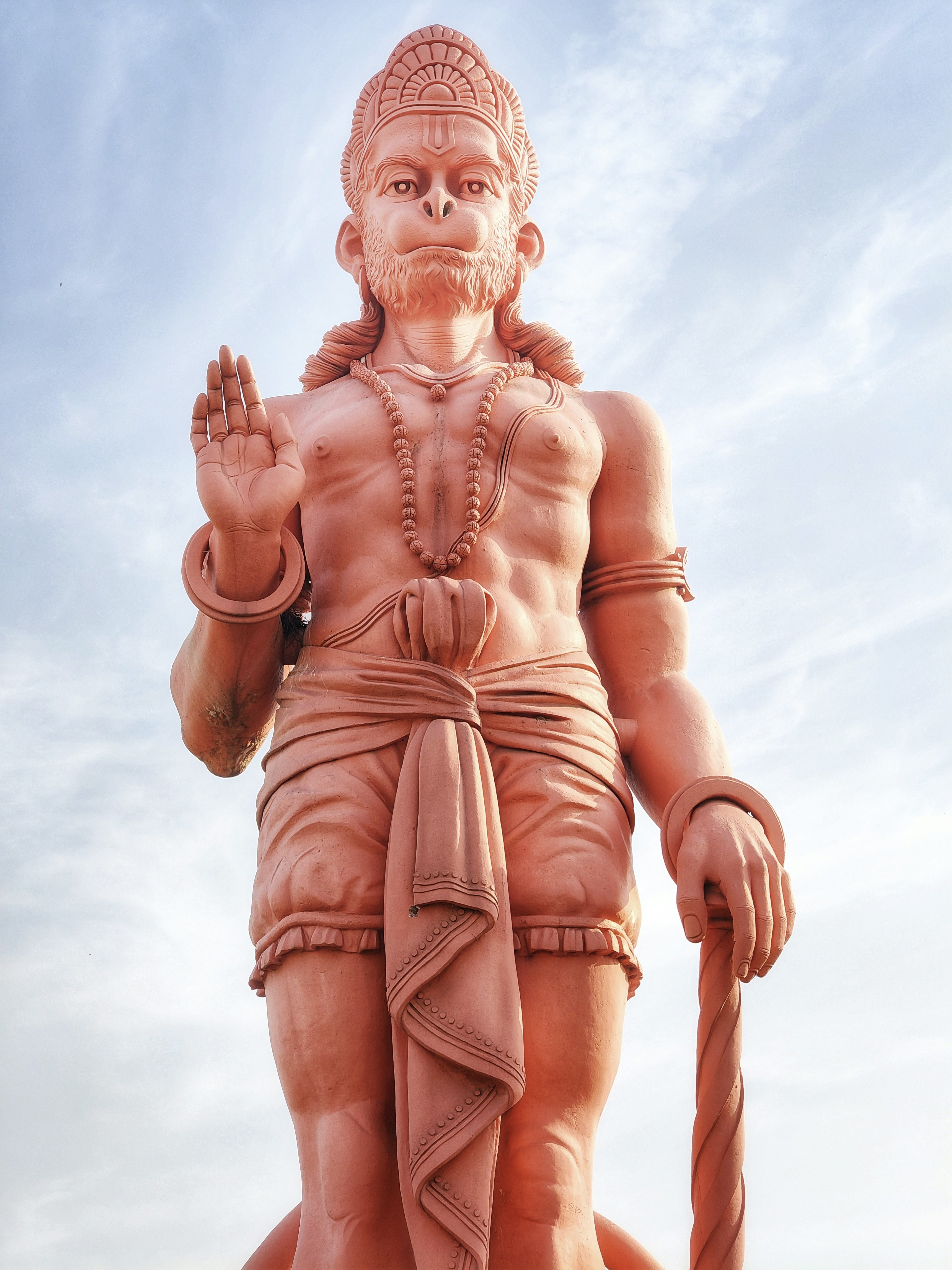 Terracotta Guardian: A Red-Hued Statue Reaching Toward the Sky