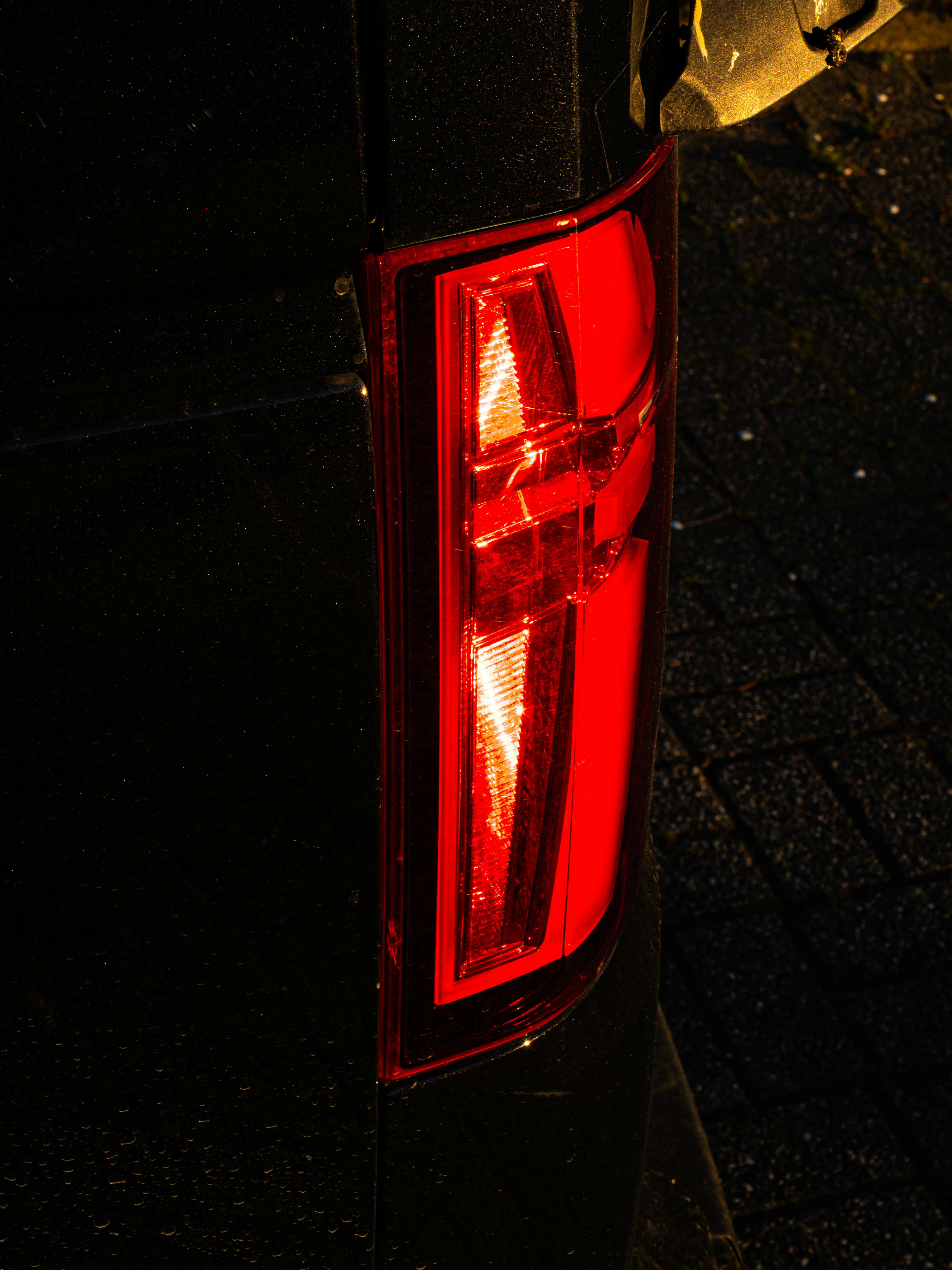 Red Tail Light in Night Rain on a Black Vehicle