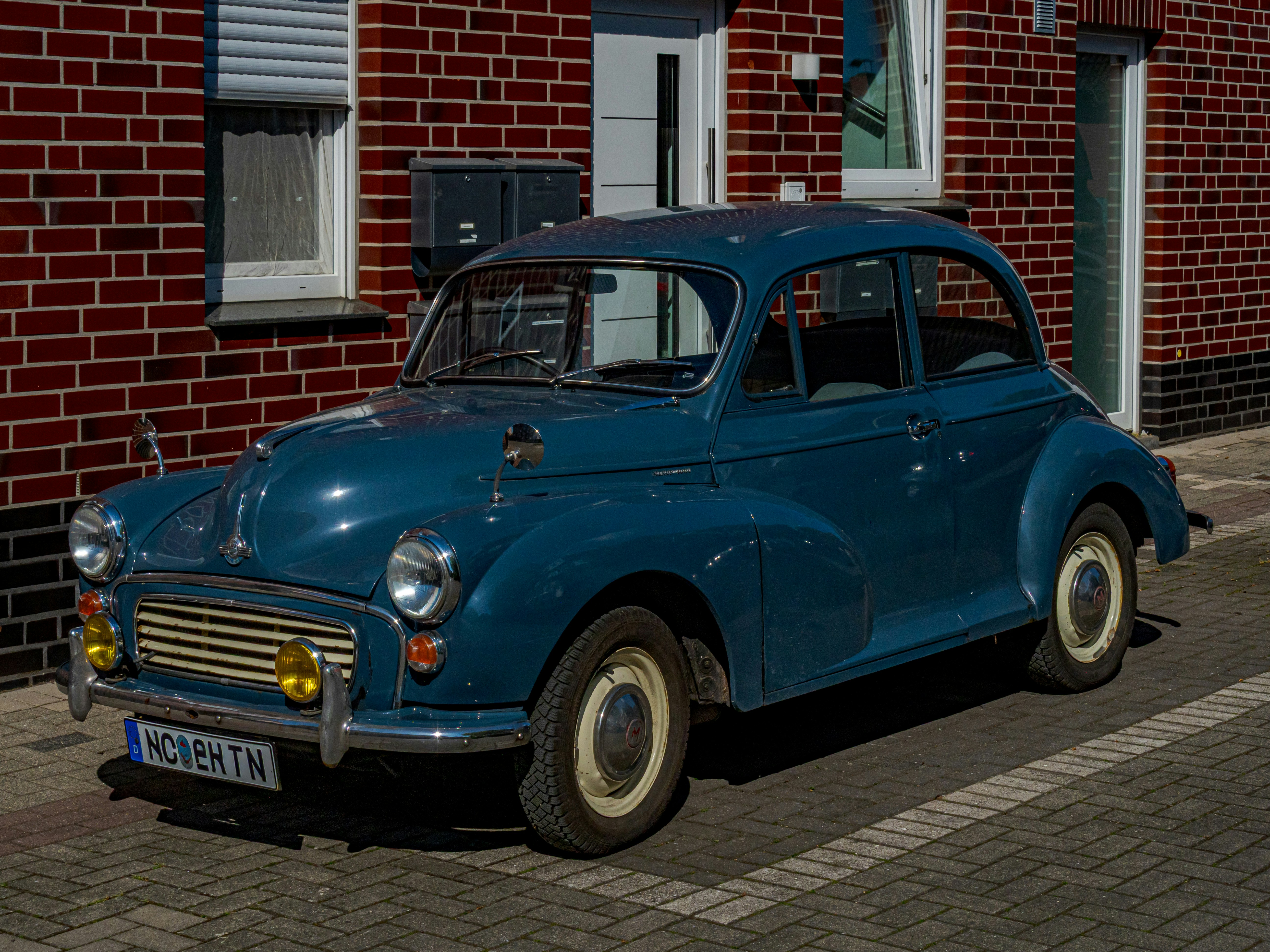 Blue vintage coupé under brick facade