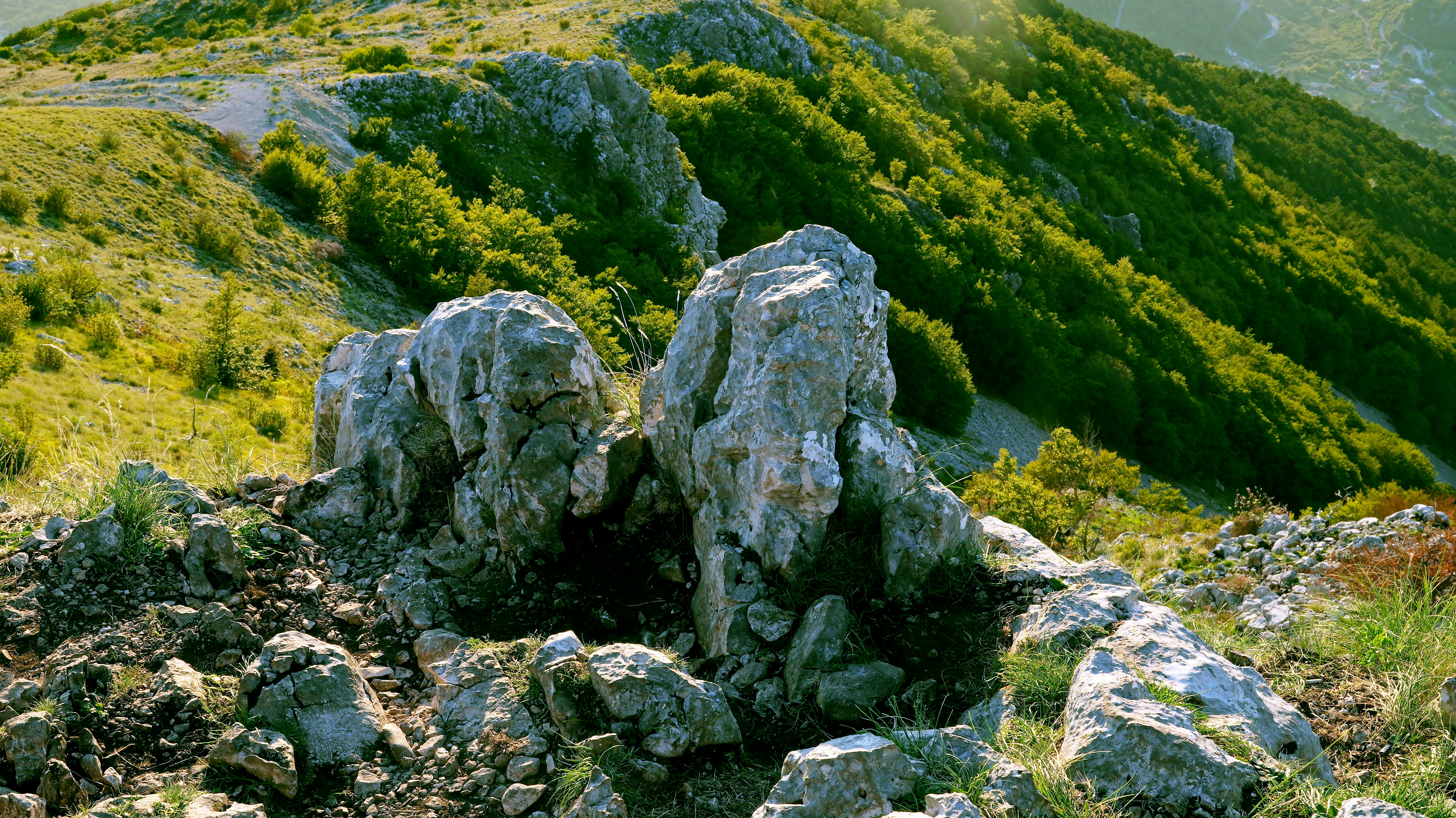 Rocky outcrop beneath sunlit ridge in a Mediterranean hillside