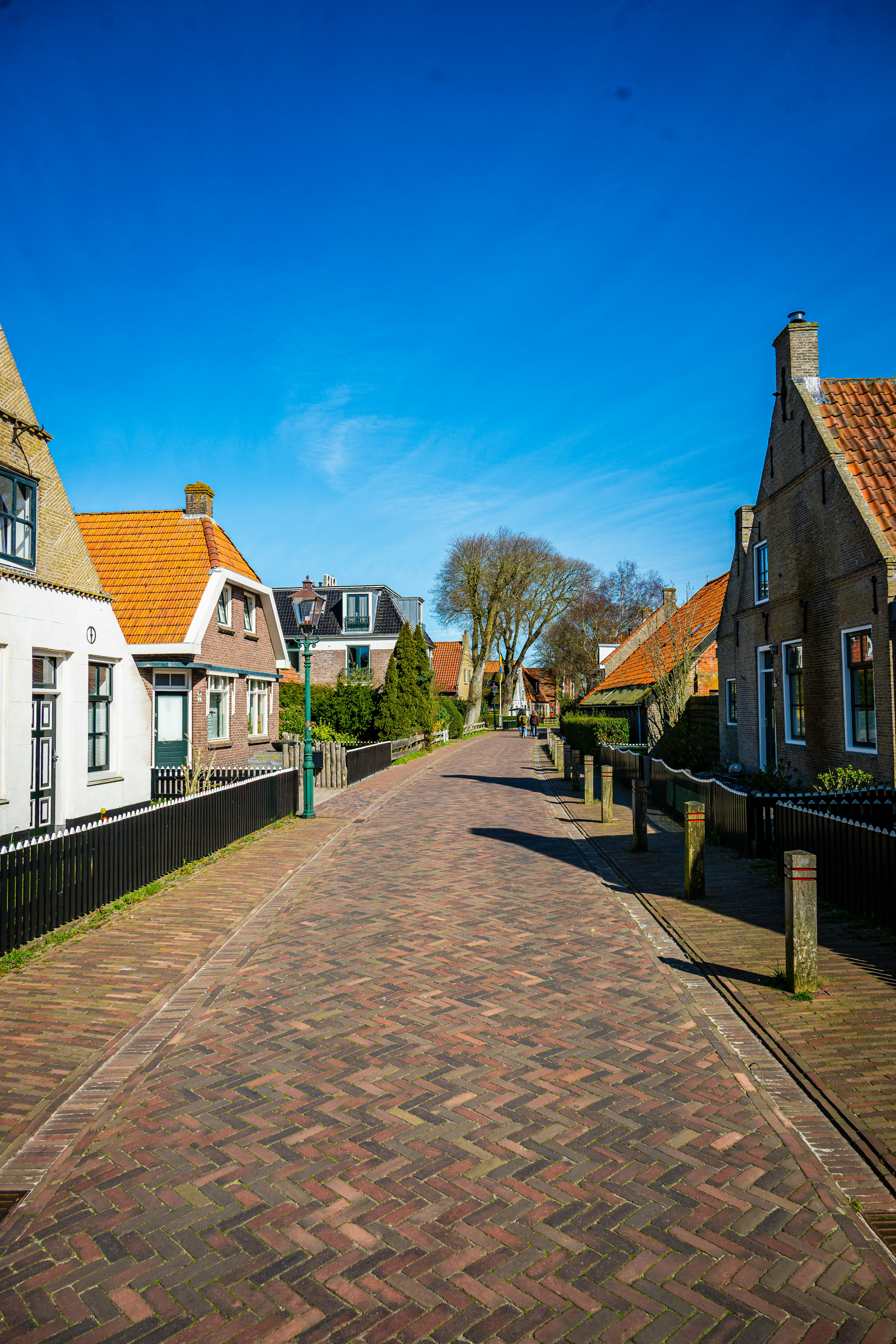 Sunlit Dutch Street: Brick Pavers, Gabled Homes, and Blue Sky