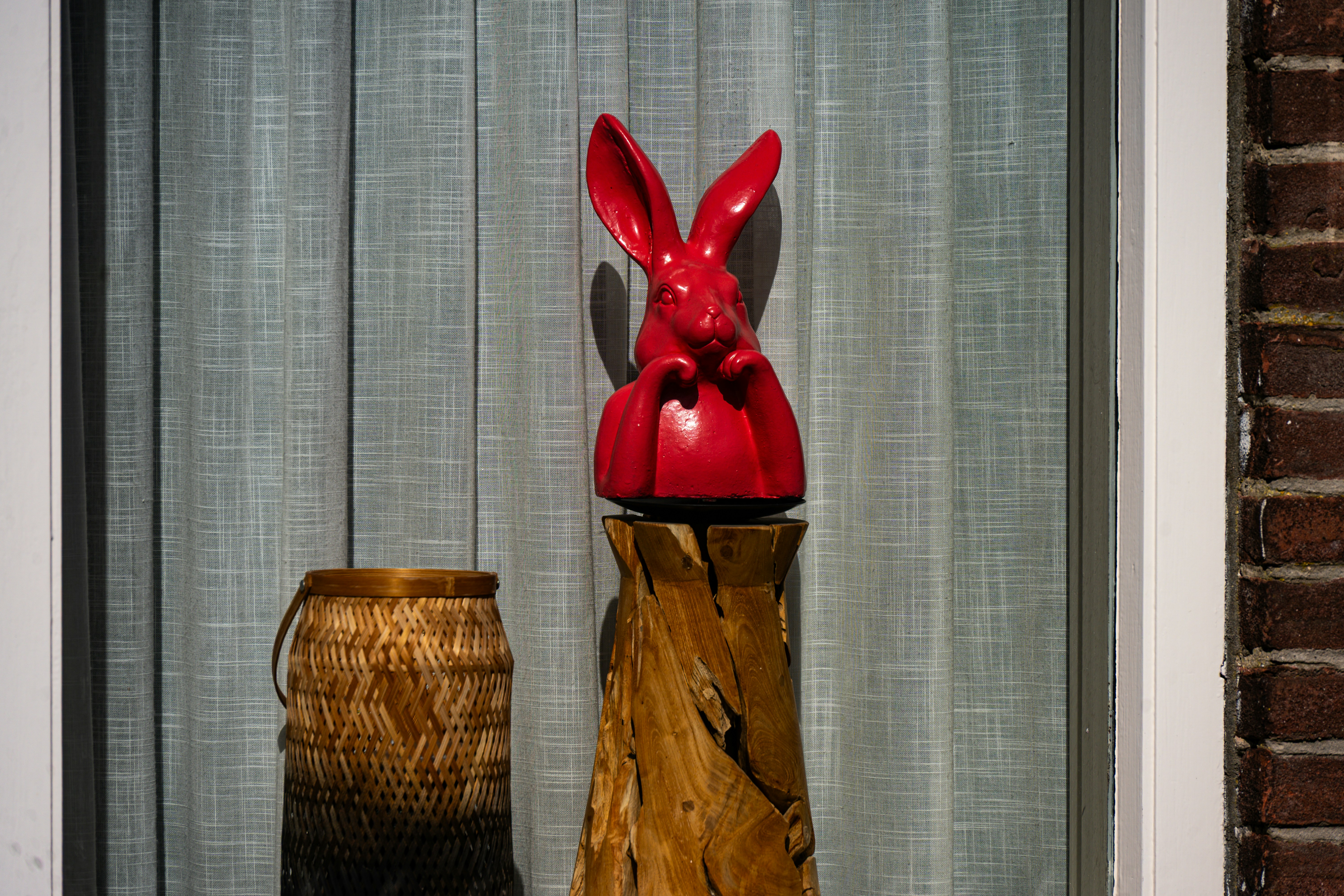 Red Bunny Sculpture Rising from a Weathered Timber Pedestal