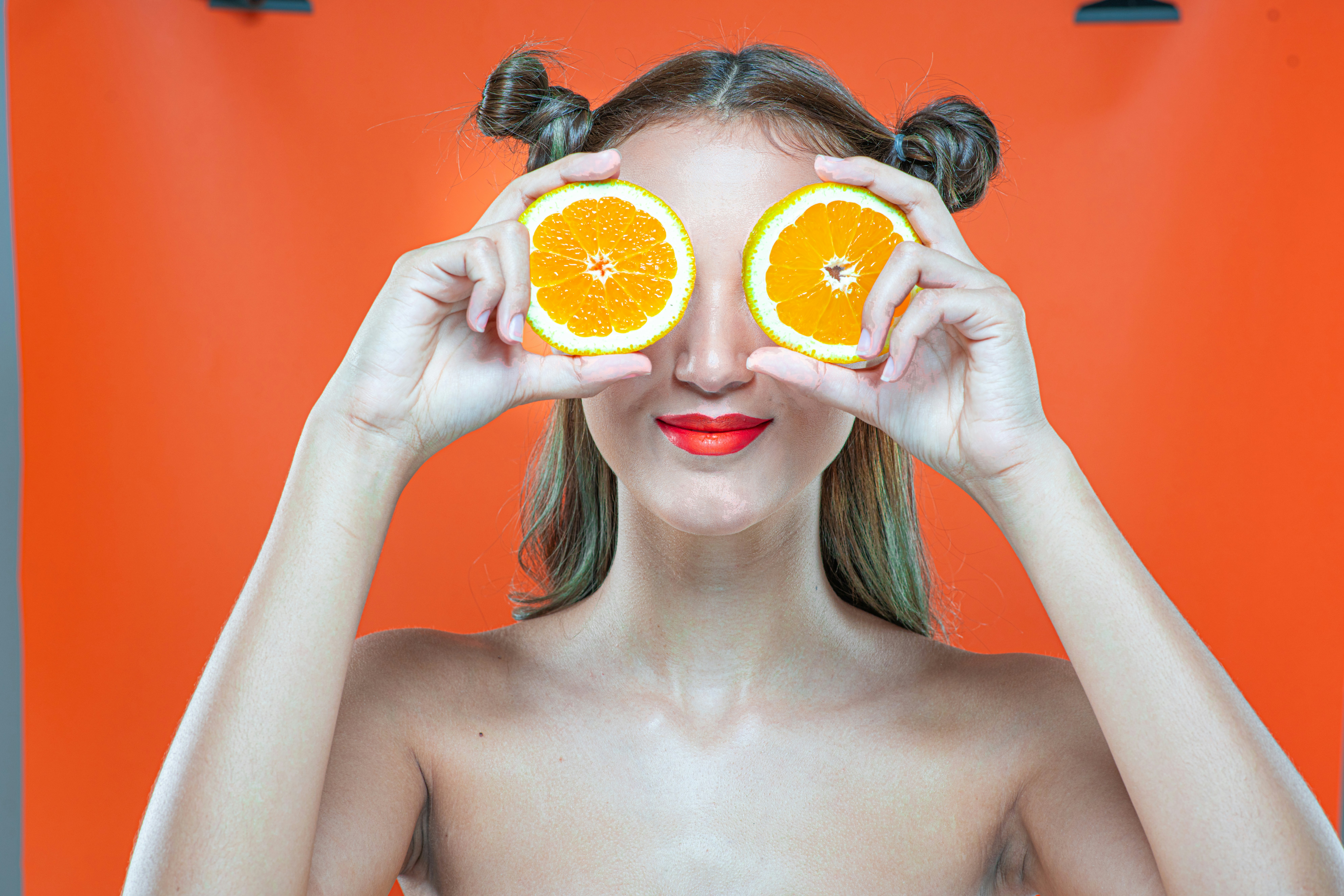 Playful Citrus Mask: Girl with Halved Oranges Framing a Bright Smile