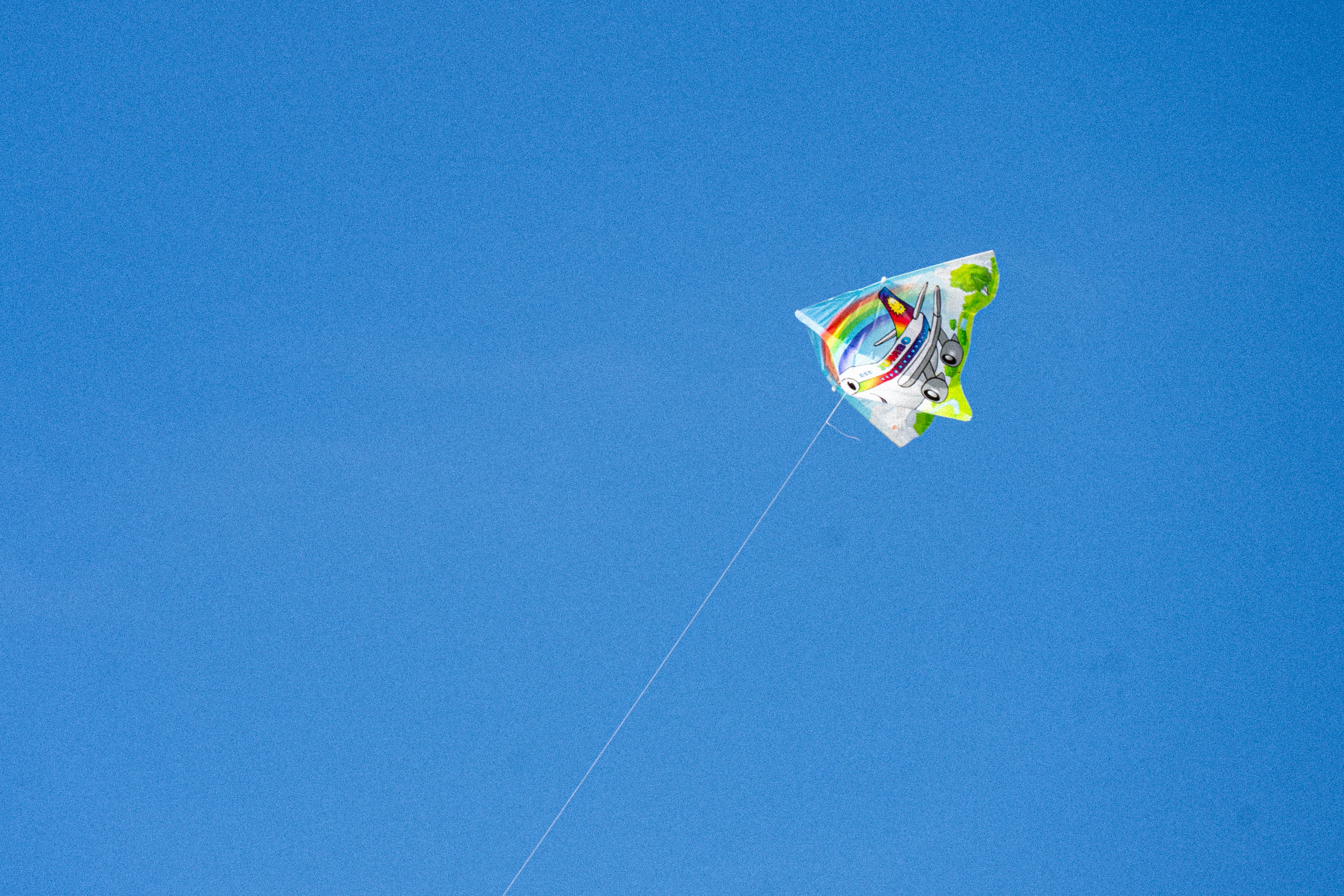 Kite Soaring: A lone tethered sail against a clear blue sky