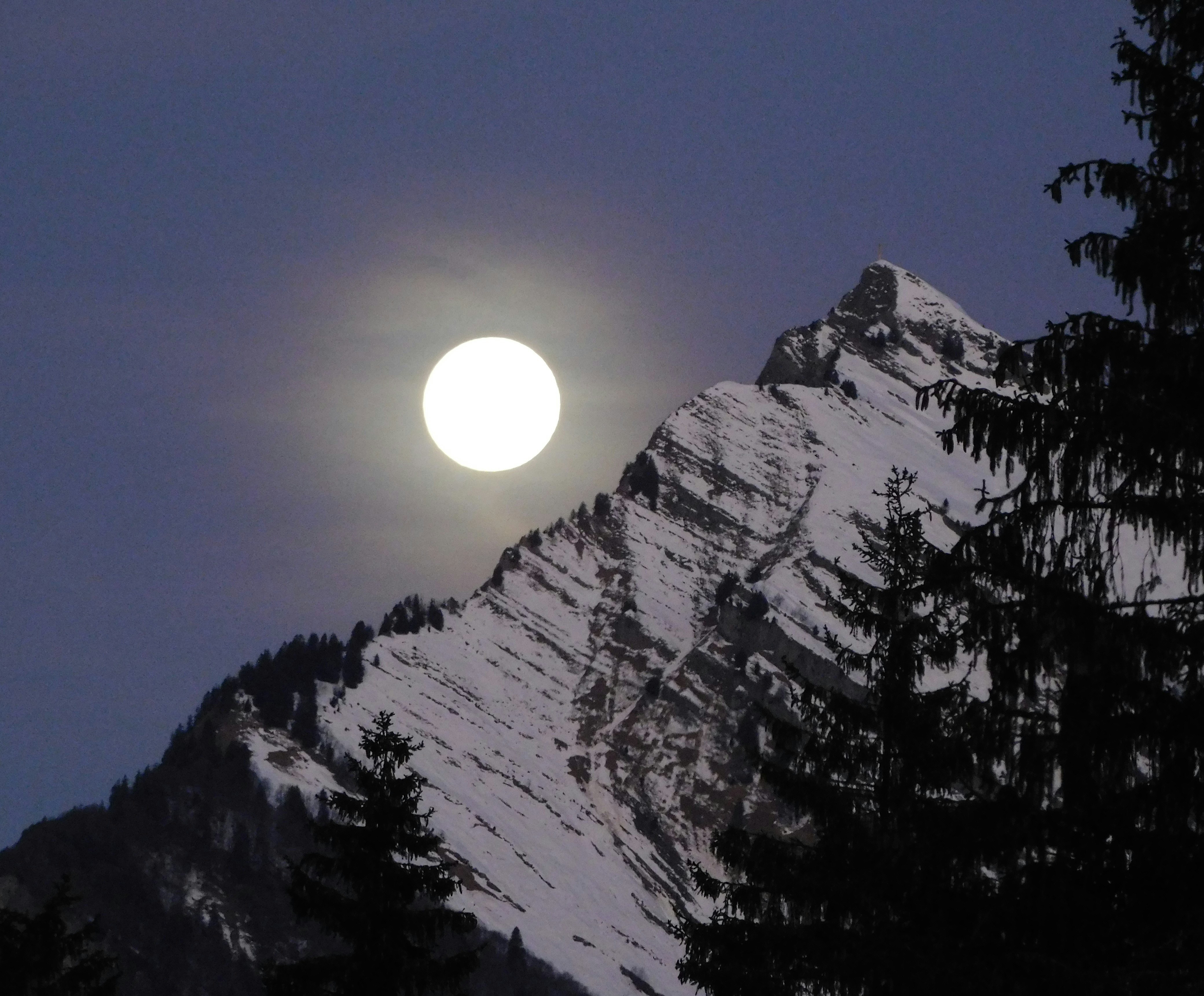 Moonlit Peak: Snow-Crowned Summit Beneath a Luminous Orb