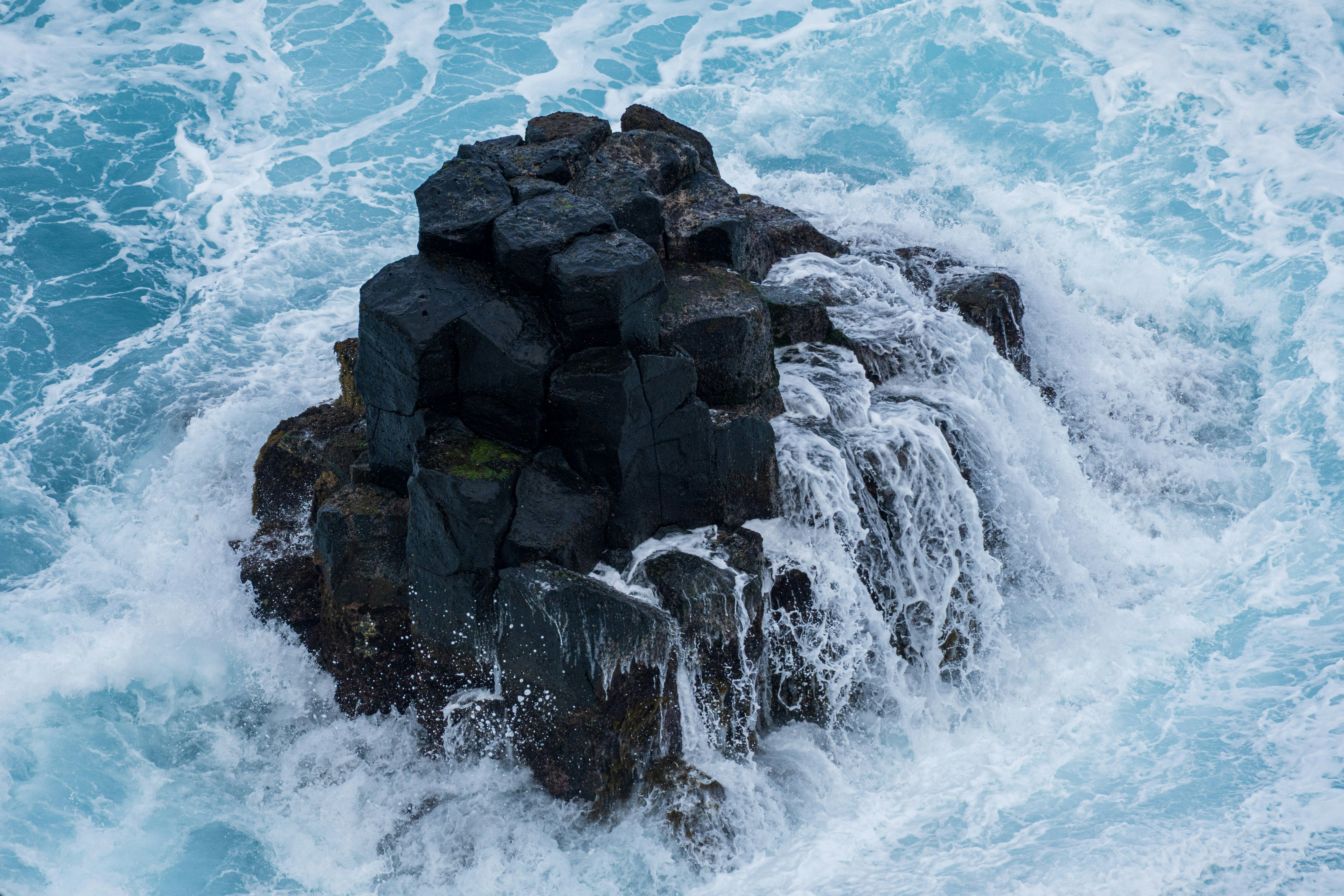 Stormbound Rock: Dark Boulders Amid Turquoise Breakers