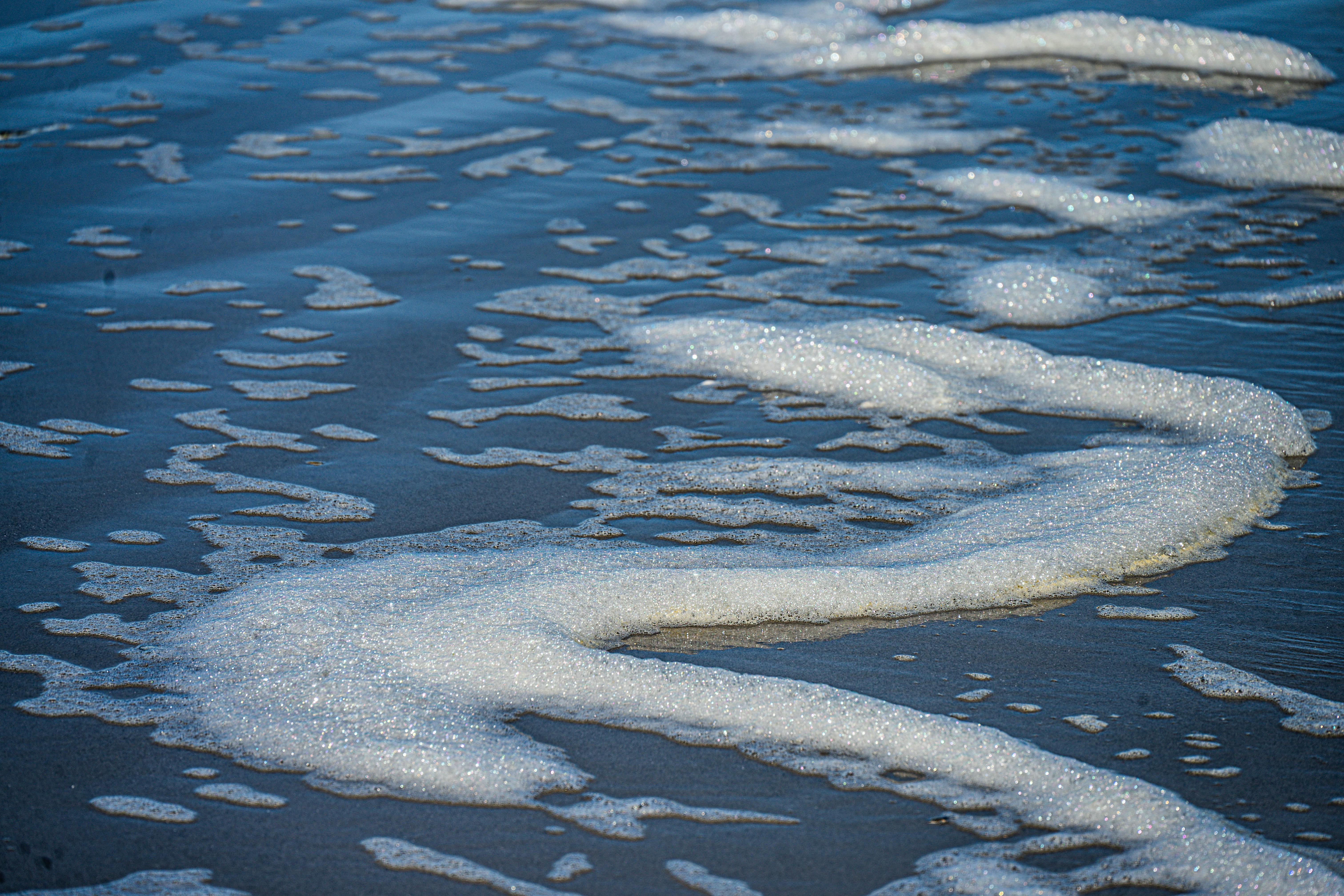 Curved Foam Trails on Blue Ice: Nature's Serpentine Lace