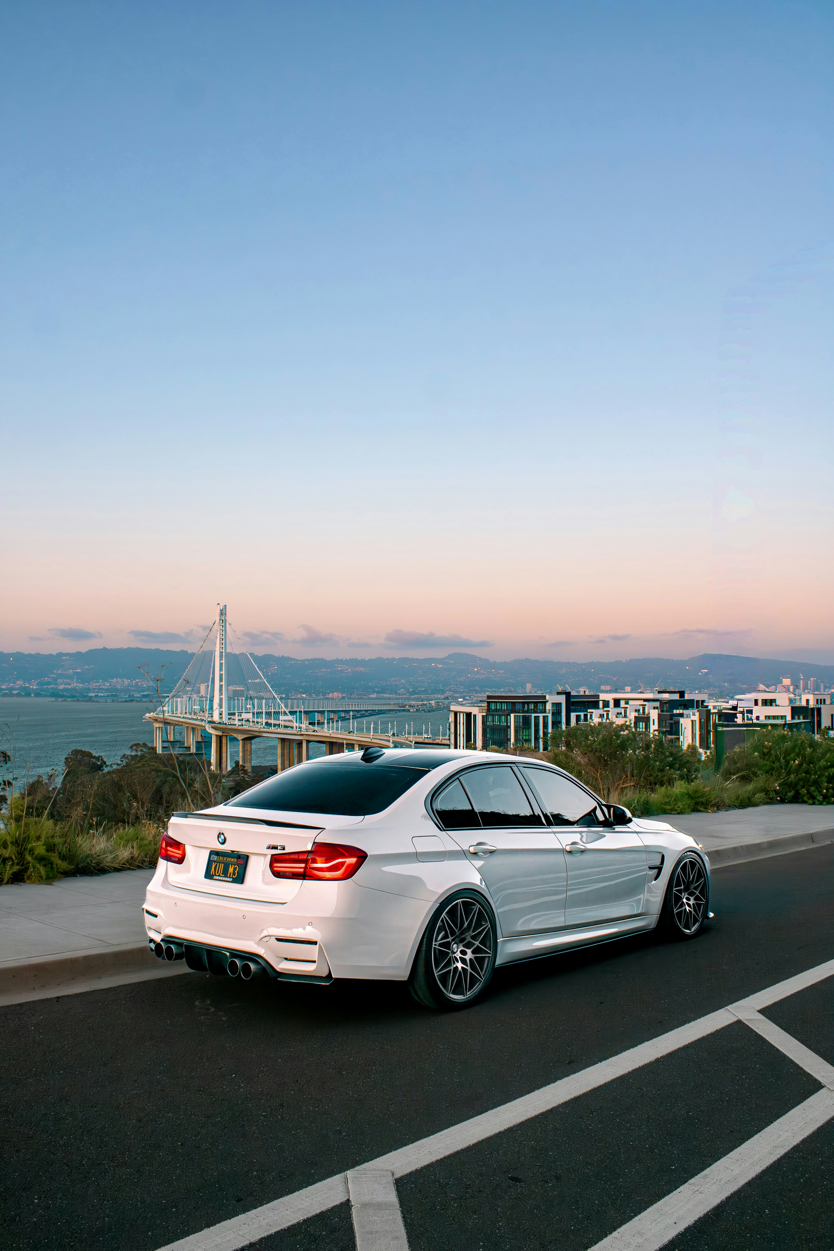 Sunset Over the Bay: A White BMW Resting Along a Coastal Road