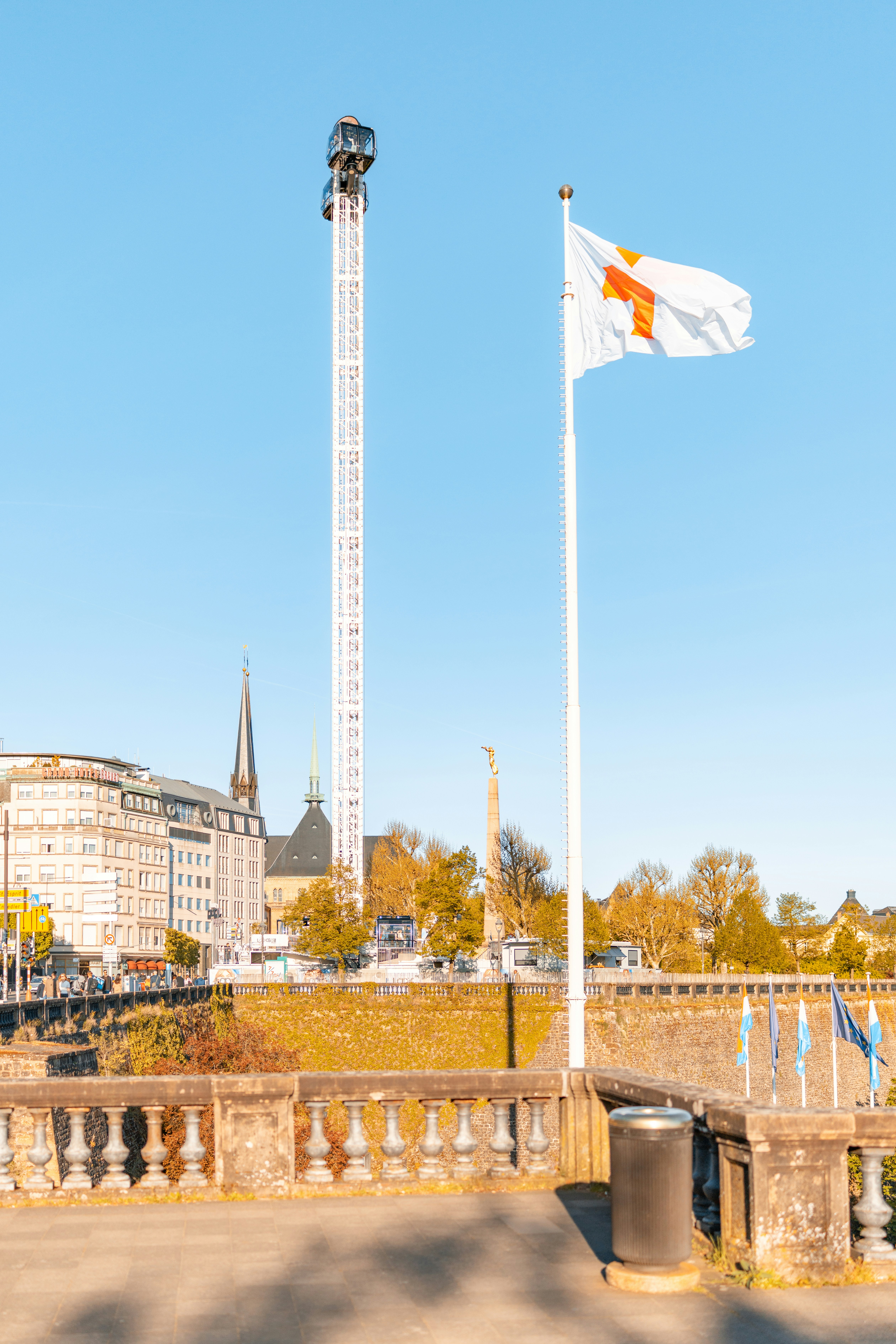 Flag Above the Riverfront: A Quiet Cityscape Under a Clear Sky