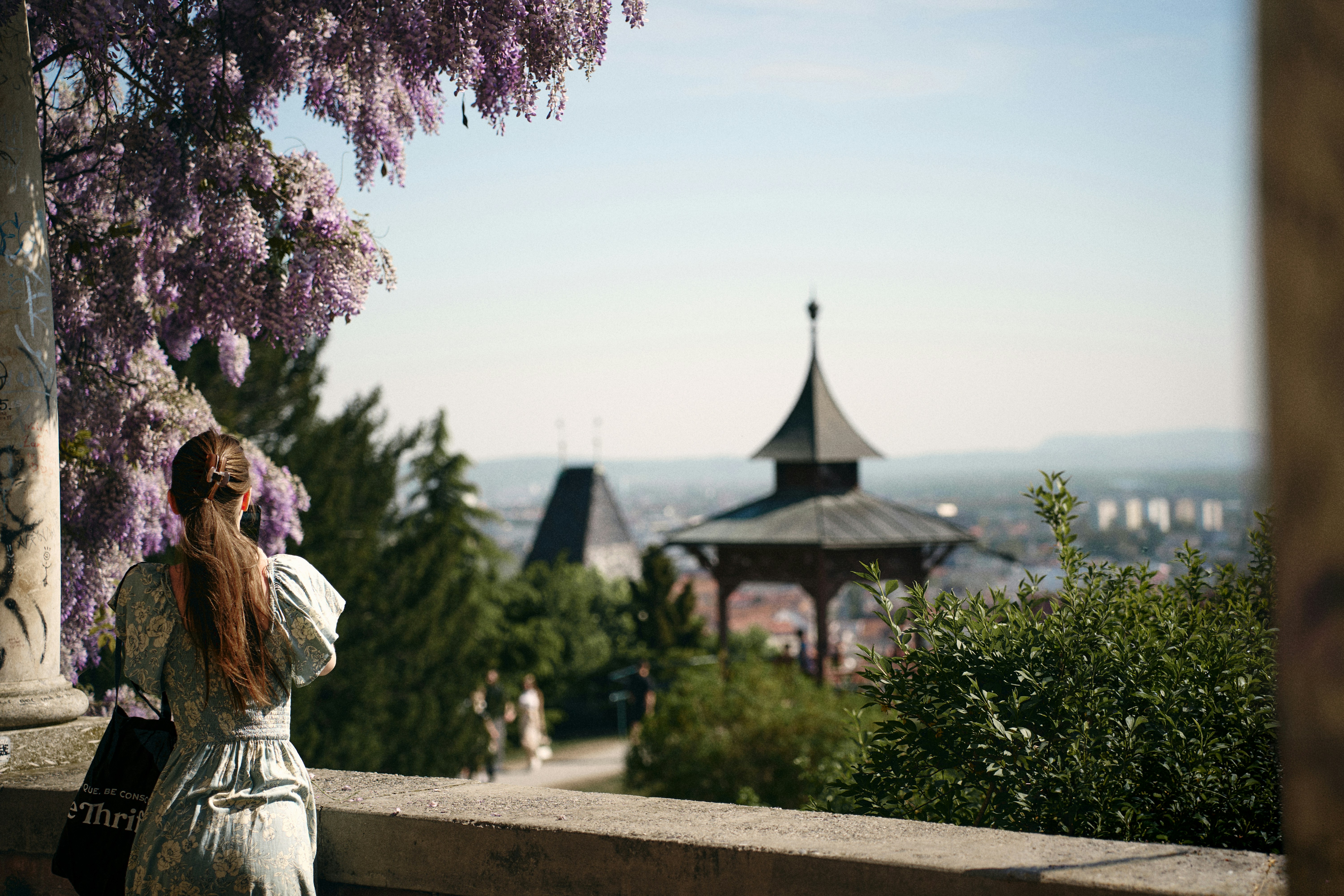 Girl in a light dress overlooking a pagoda garden at sunset