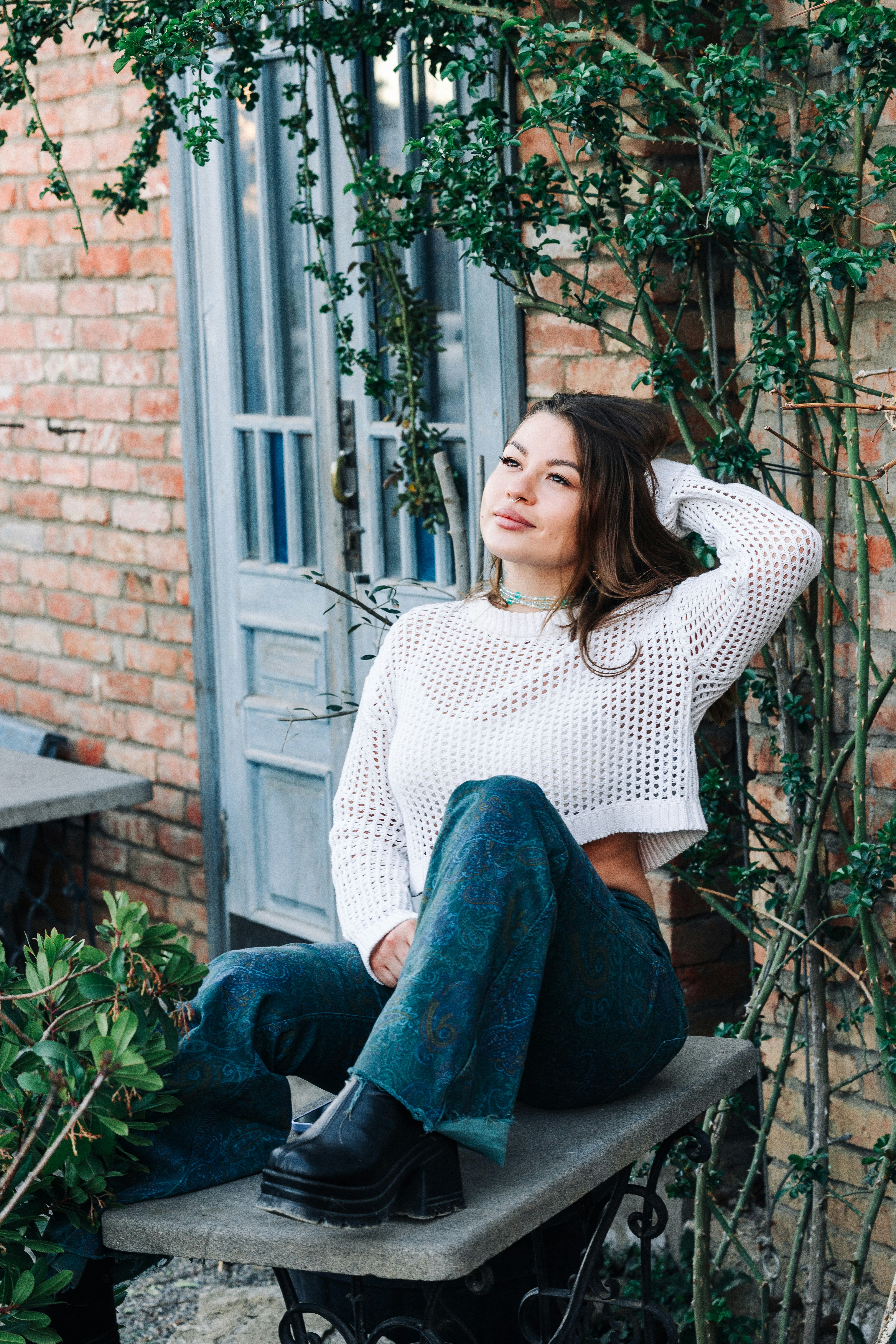 Relaxed Confidence: A Woman Leaning on a Brick Wall Courtyard