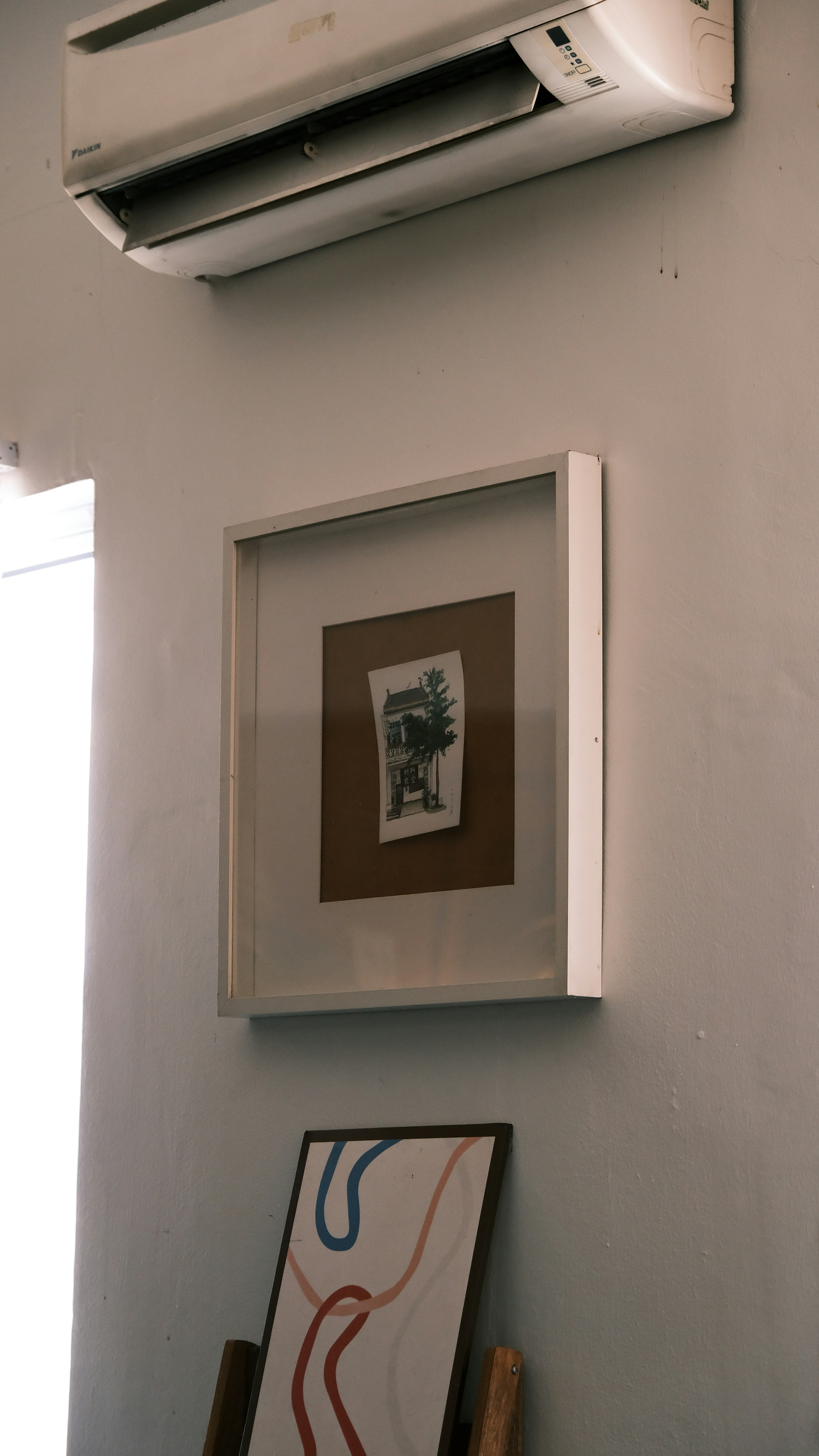 Muted Geometry: Framed Art and Air Conditioner in Soft Light