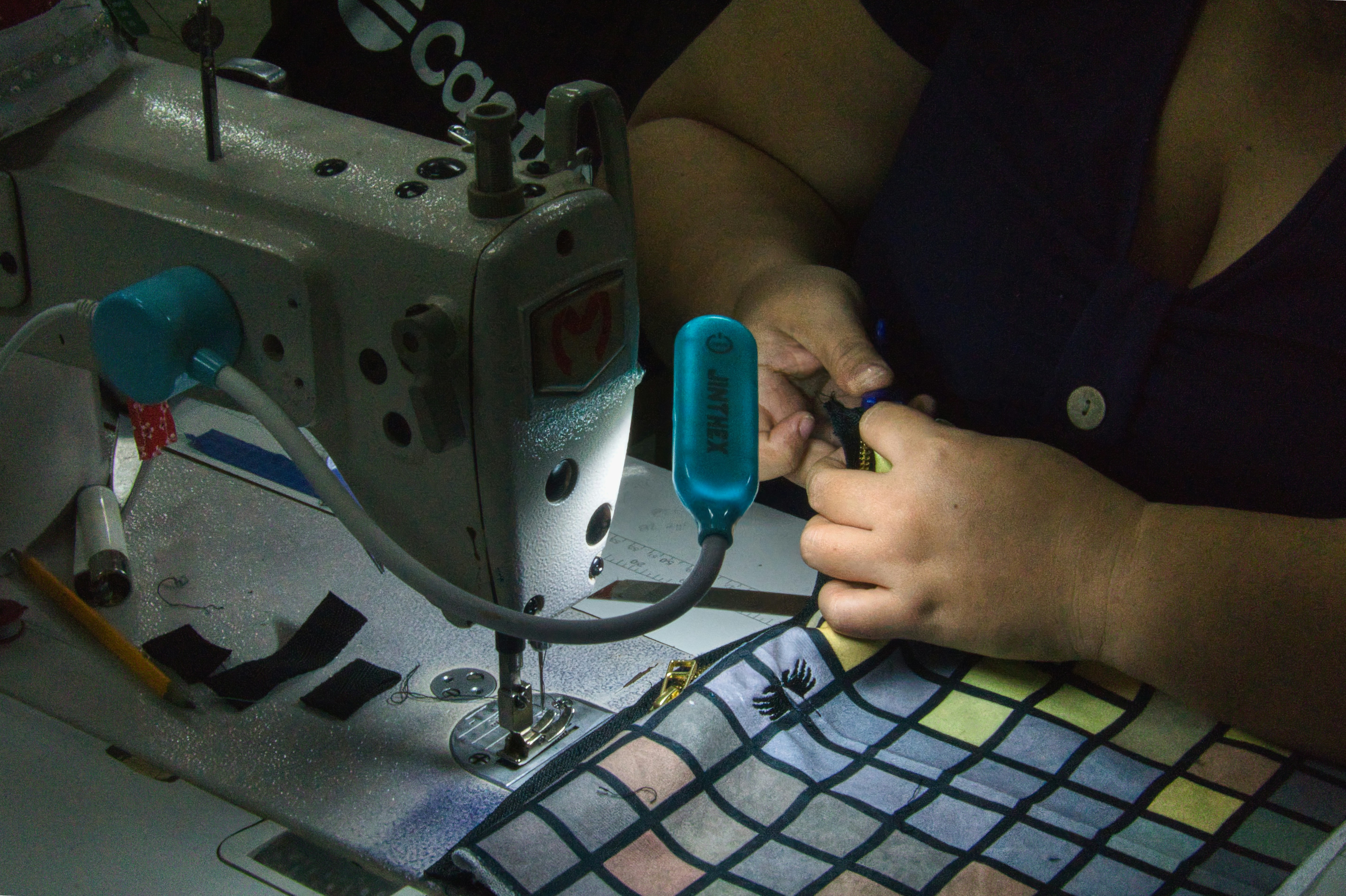 Fingers at Work: Threading a Tiny Blue Tool Beneath the Sewing Machine
