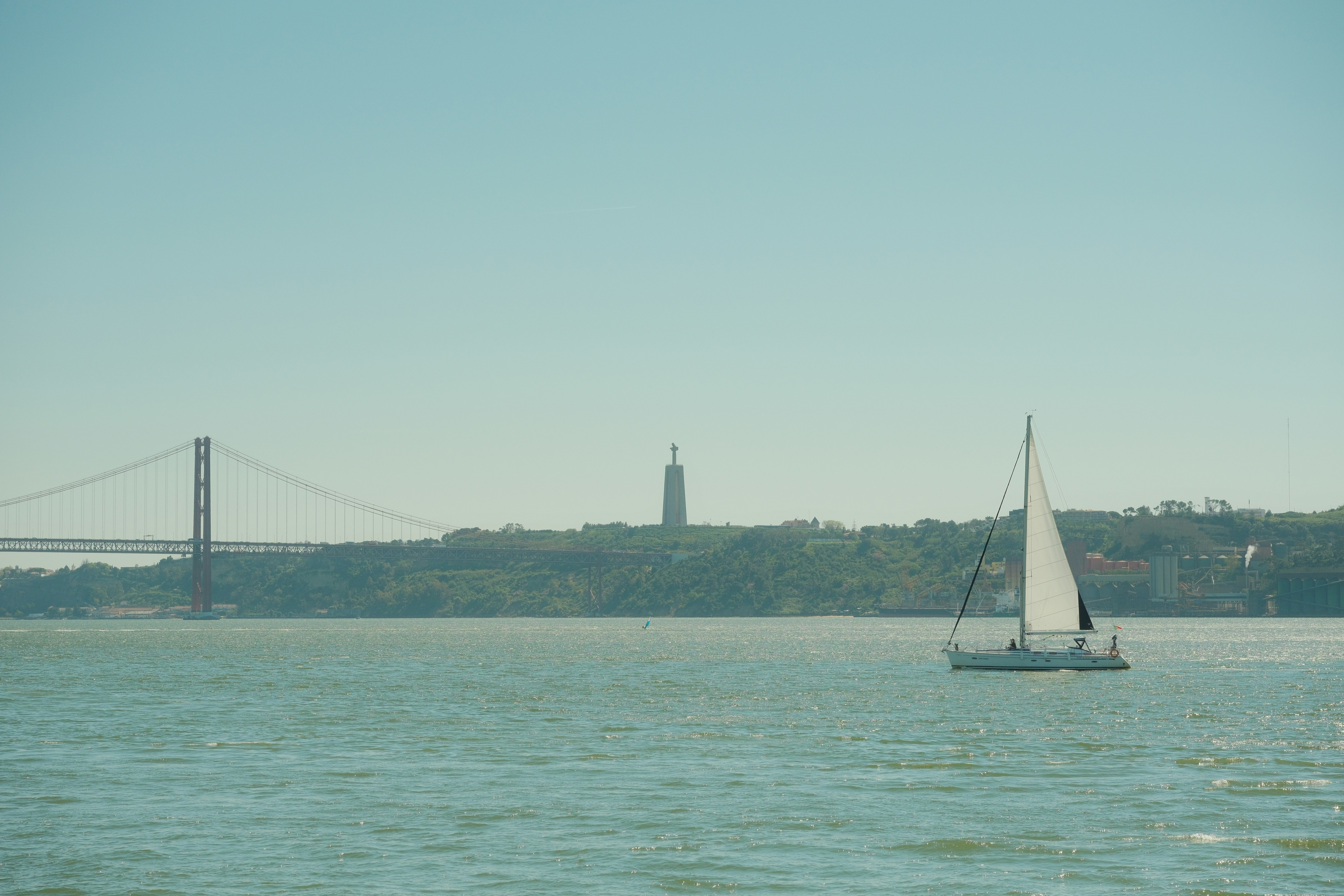 Sailboat on a Calm Estuary under a Pale Sky