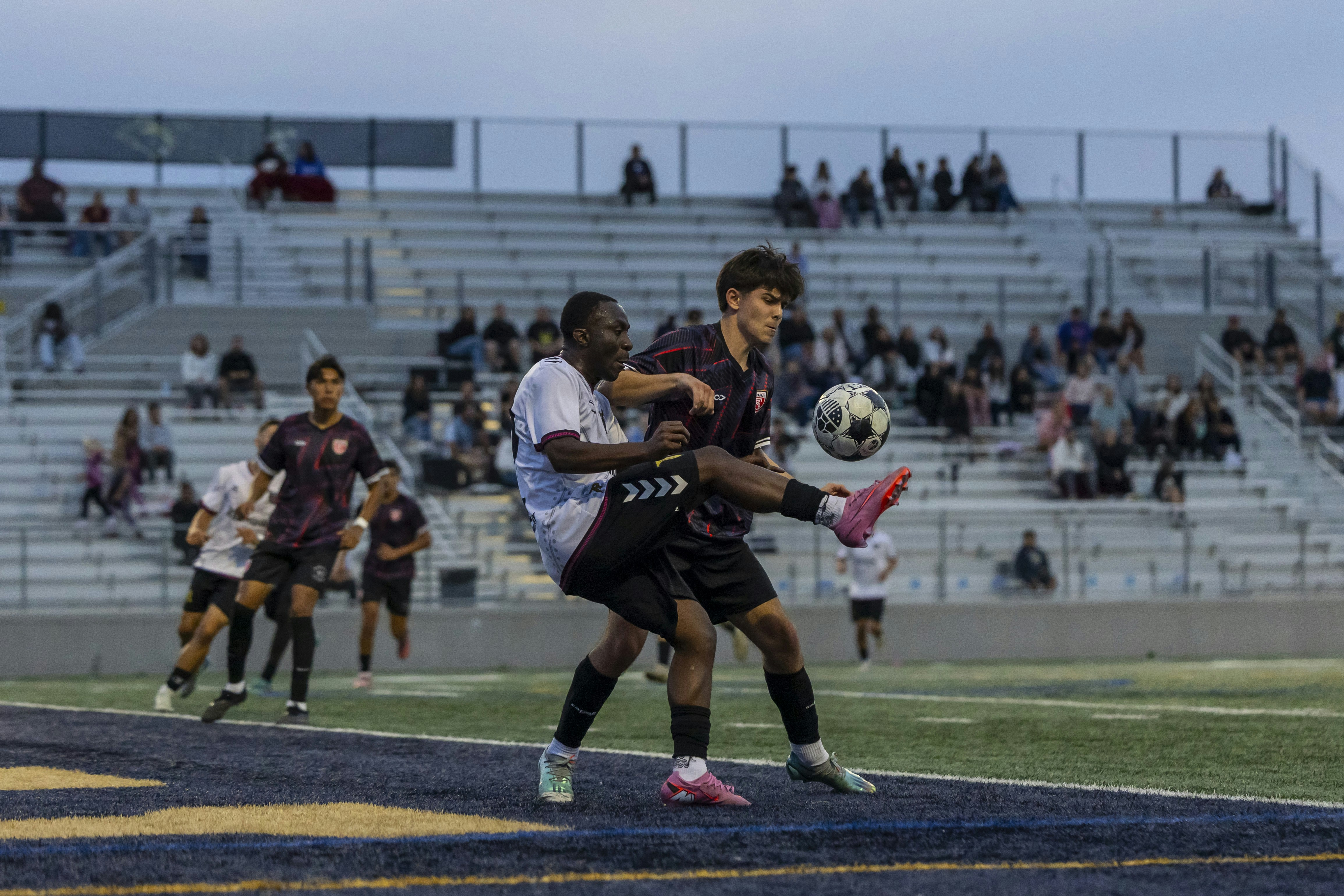 Midflight Challenge: Two Players Contest a Ball on a Turf Field