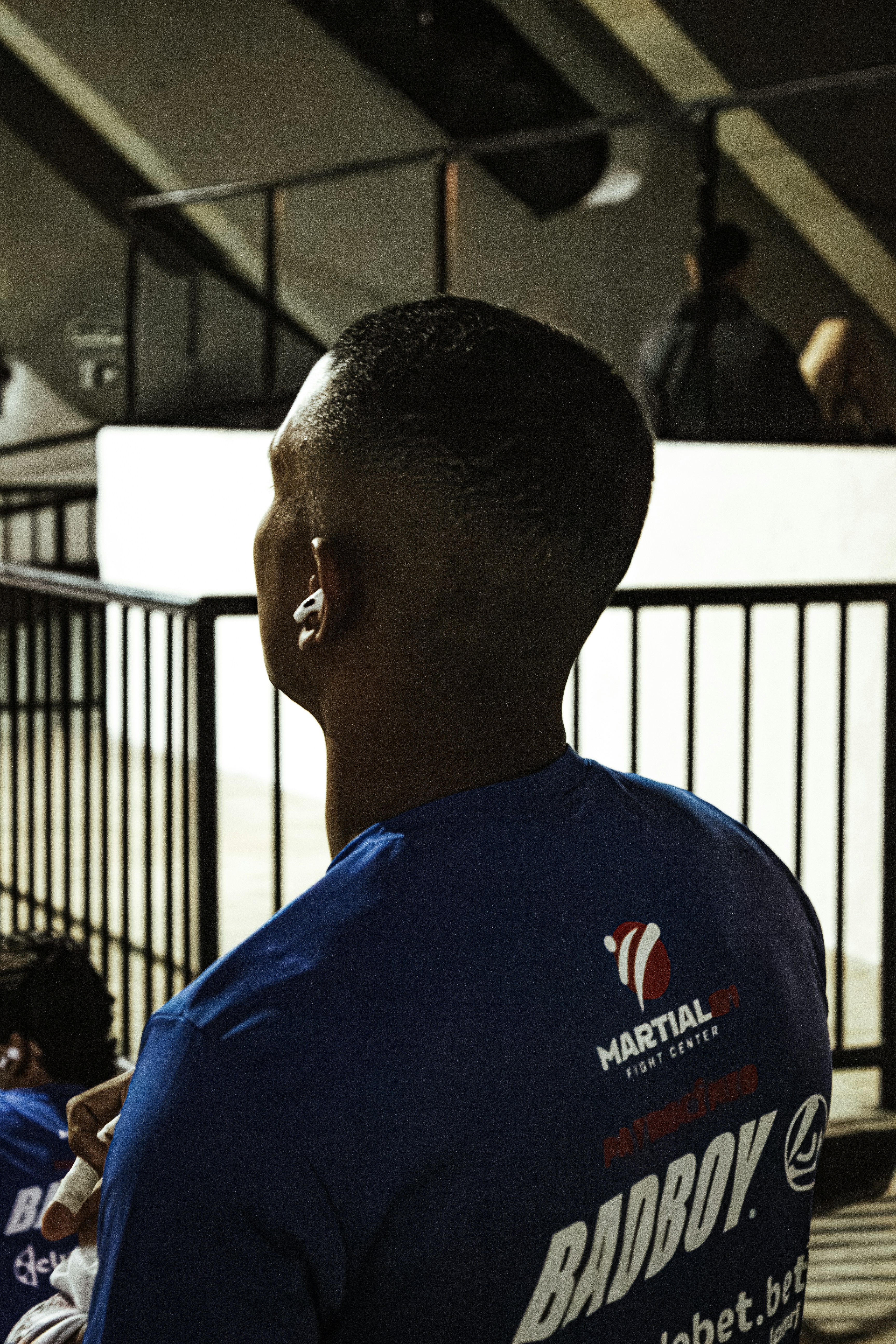 Back of a blue-shirted martial arts student at training facility
