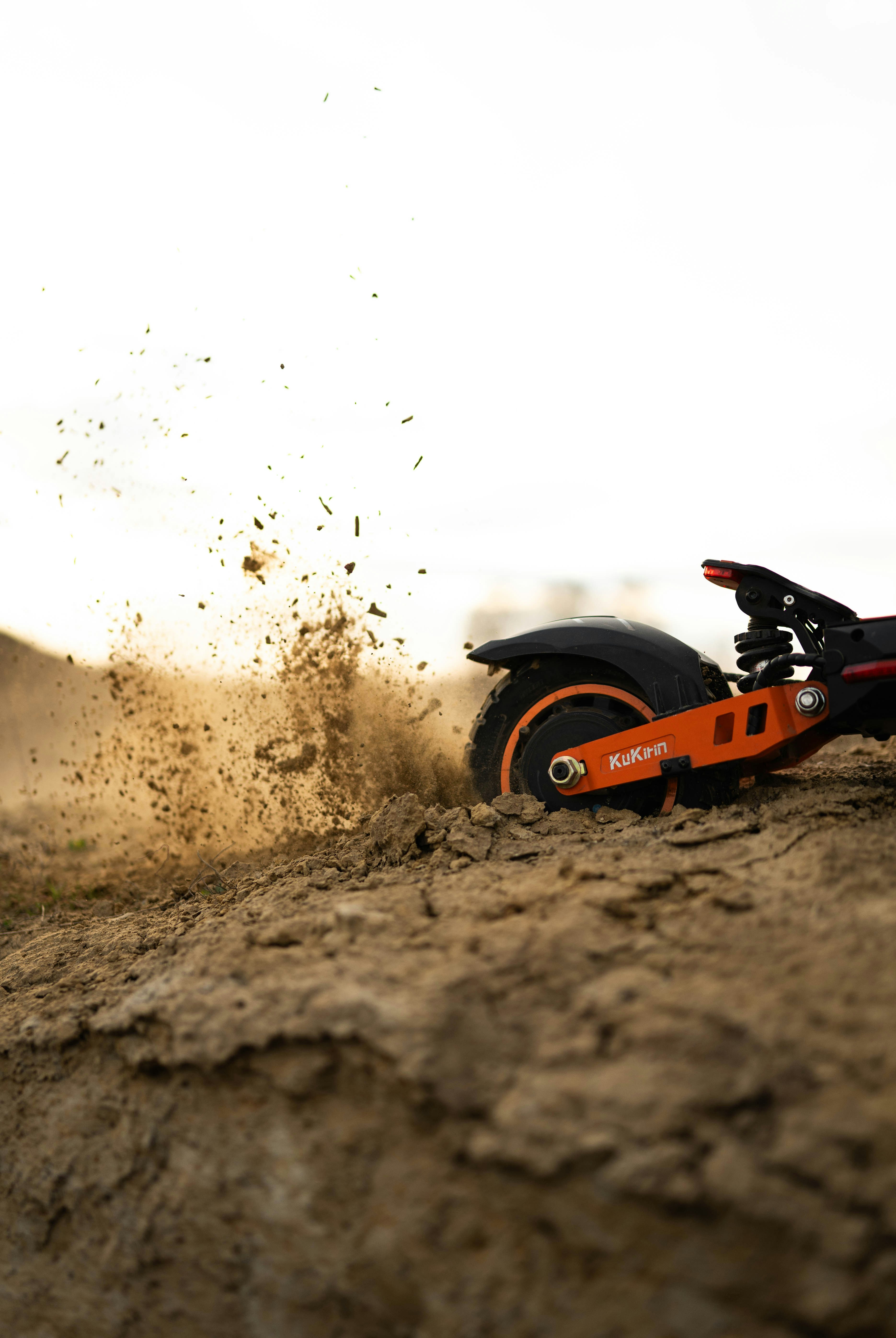 Orange crawler skids up a dirt ramp as dust flies