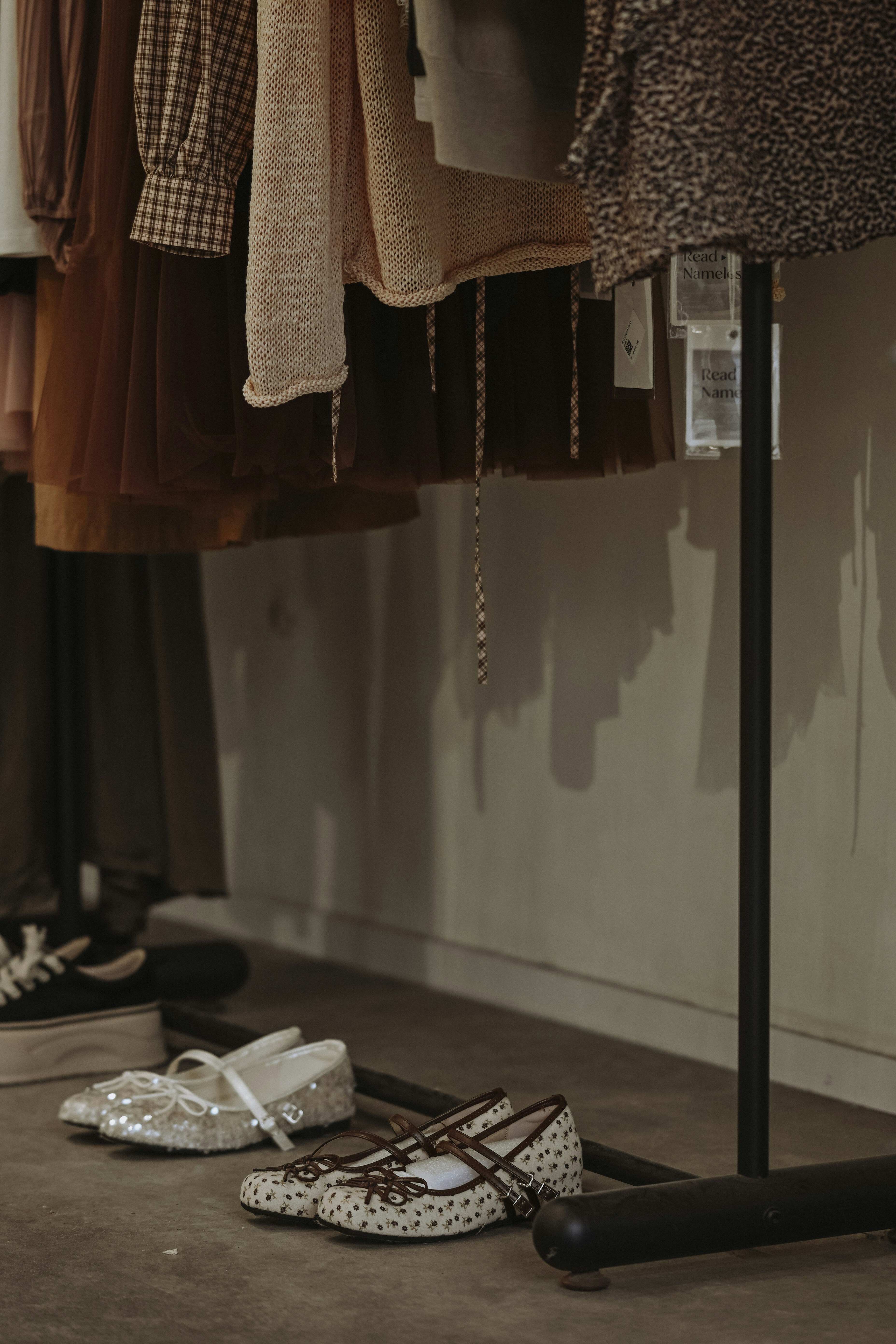 Last Pair, First Light: Shoes Beneath a Skirt Rack
