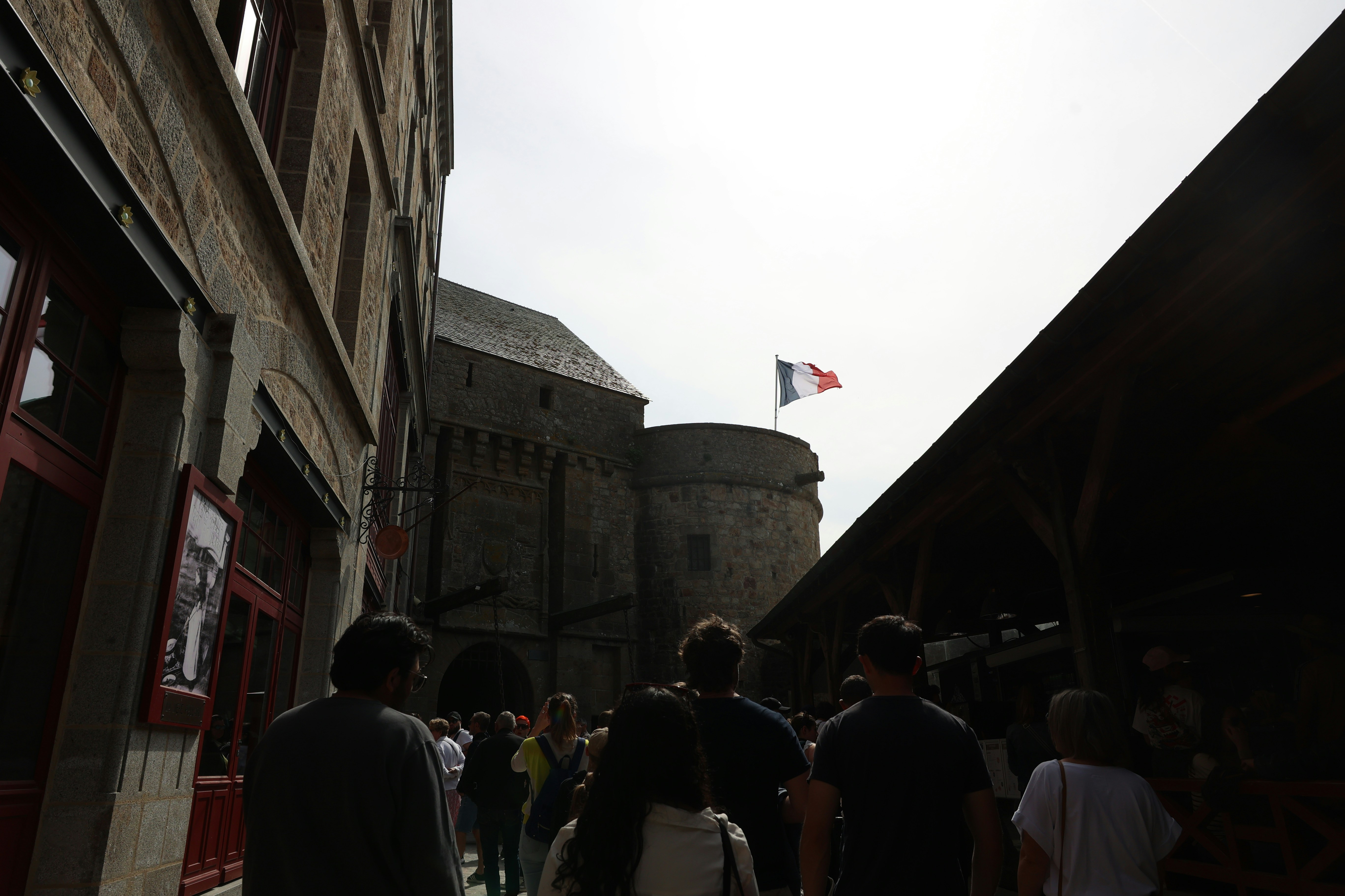 Rising Flag Over Timed Steps: A Quiet Crowd Beneath Castle Walls