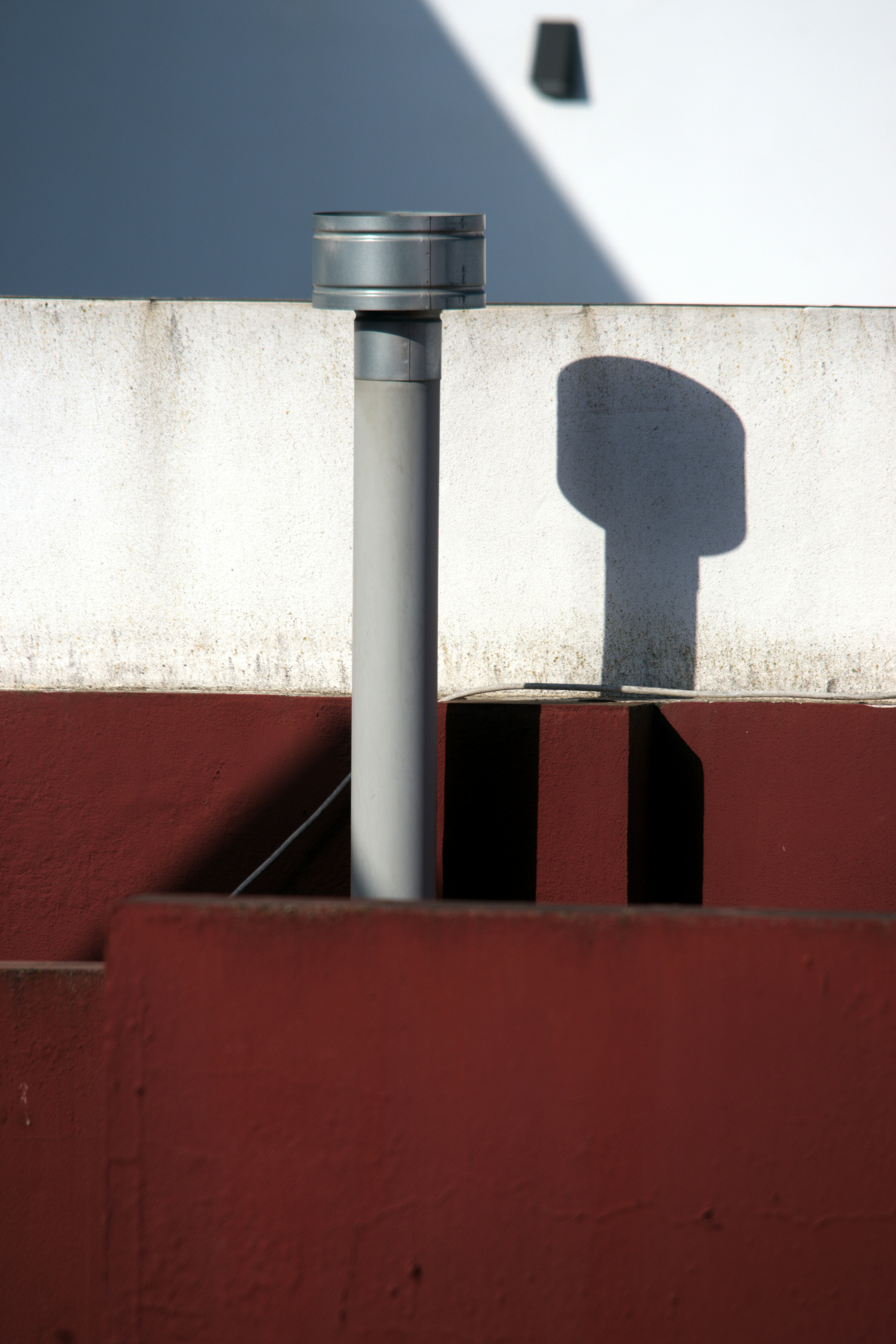 Shadowed Vent and Pipe on Sunlit Rooftop