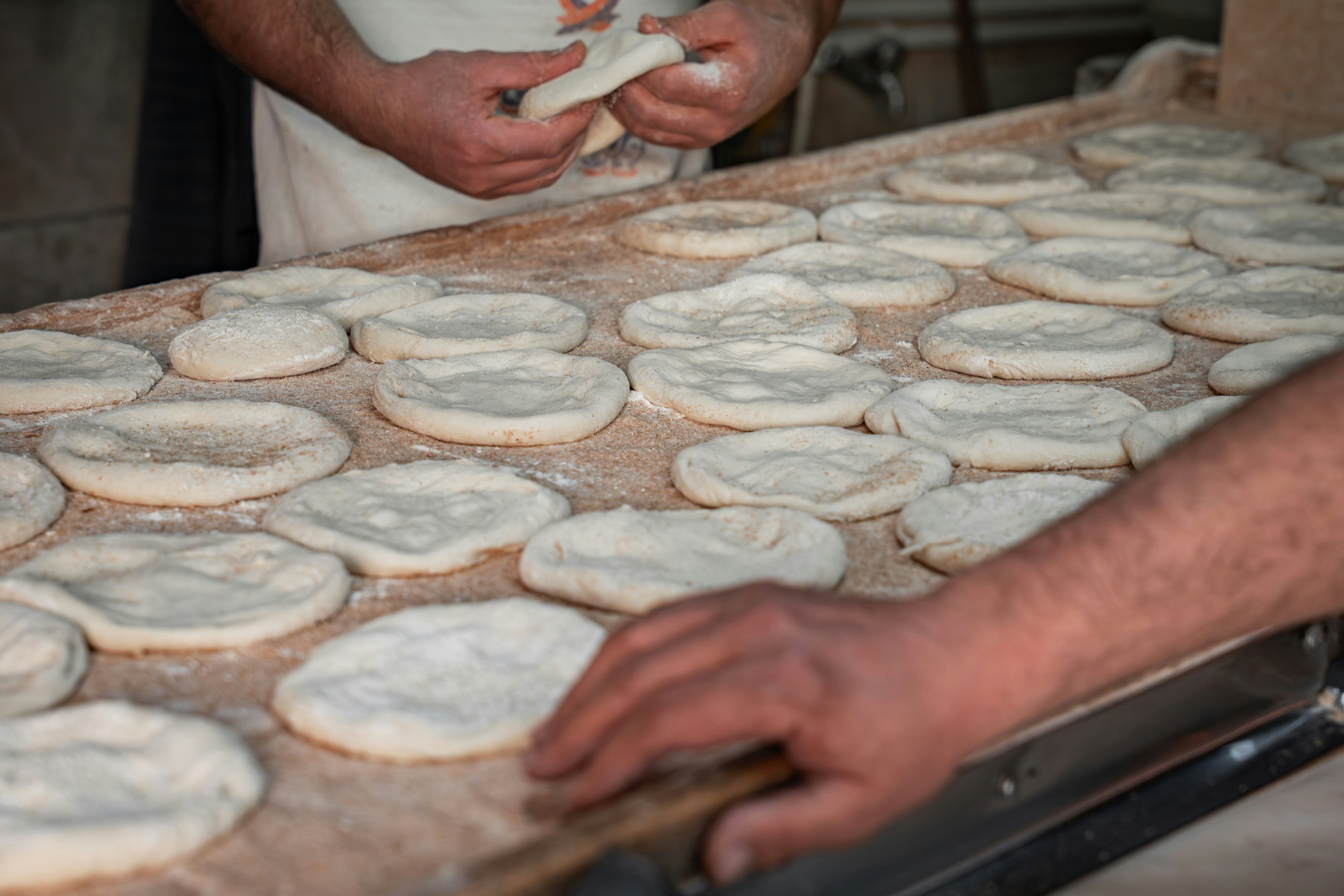 Doughy Hands at the Line: Crafting Fresh Pizzas on a Floured Conveyor