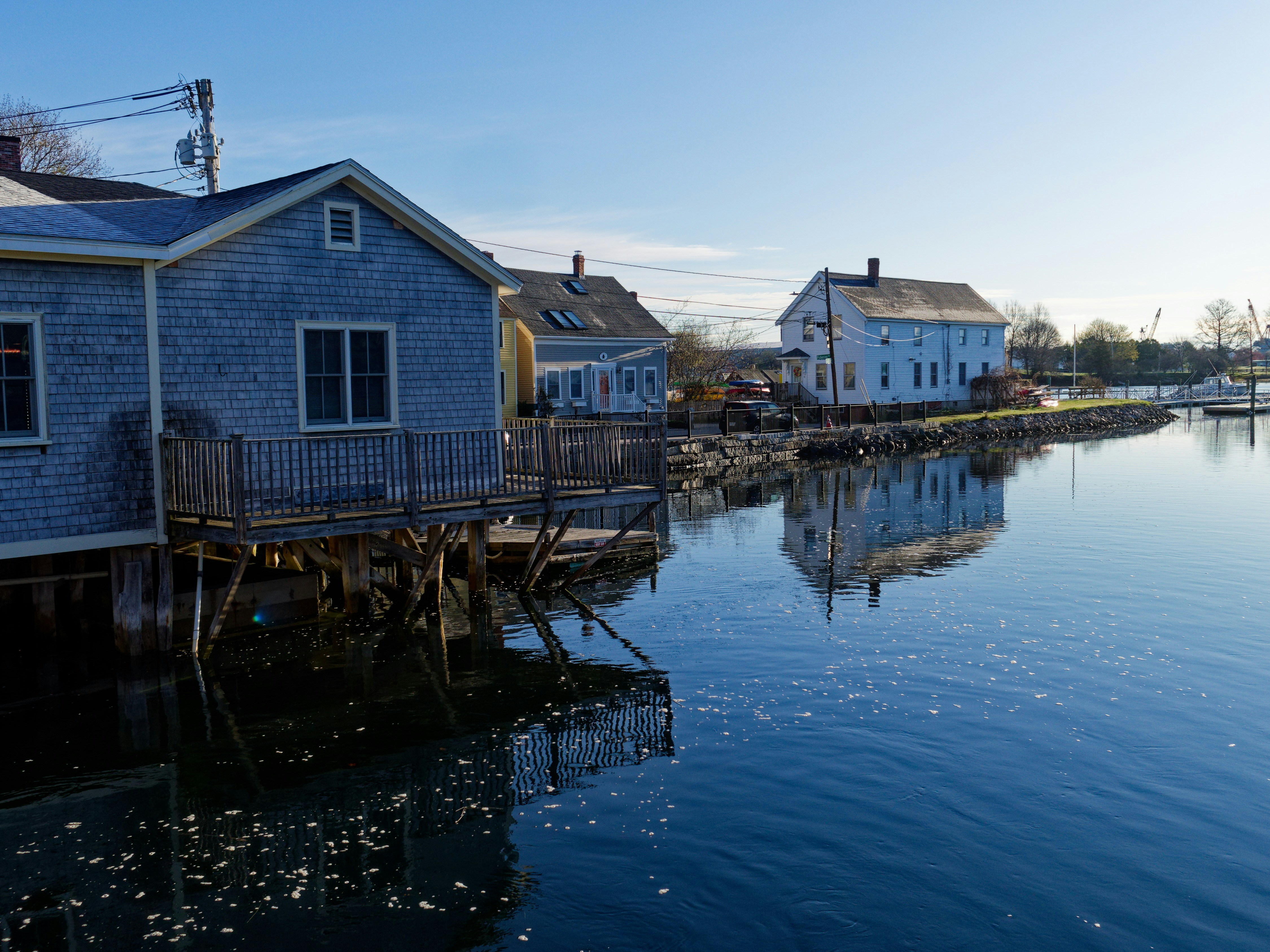 Row of blue boatside cottages mirrored on a tranquil harbor