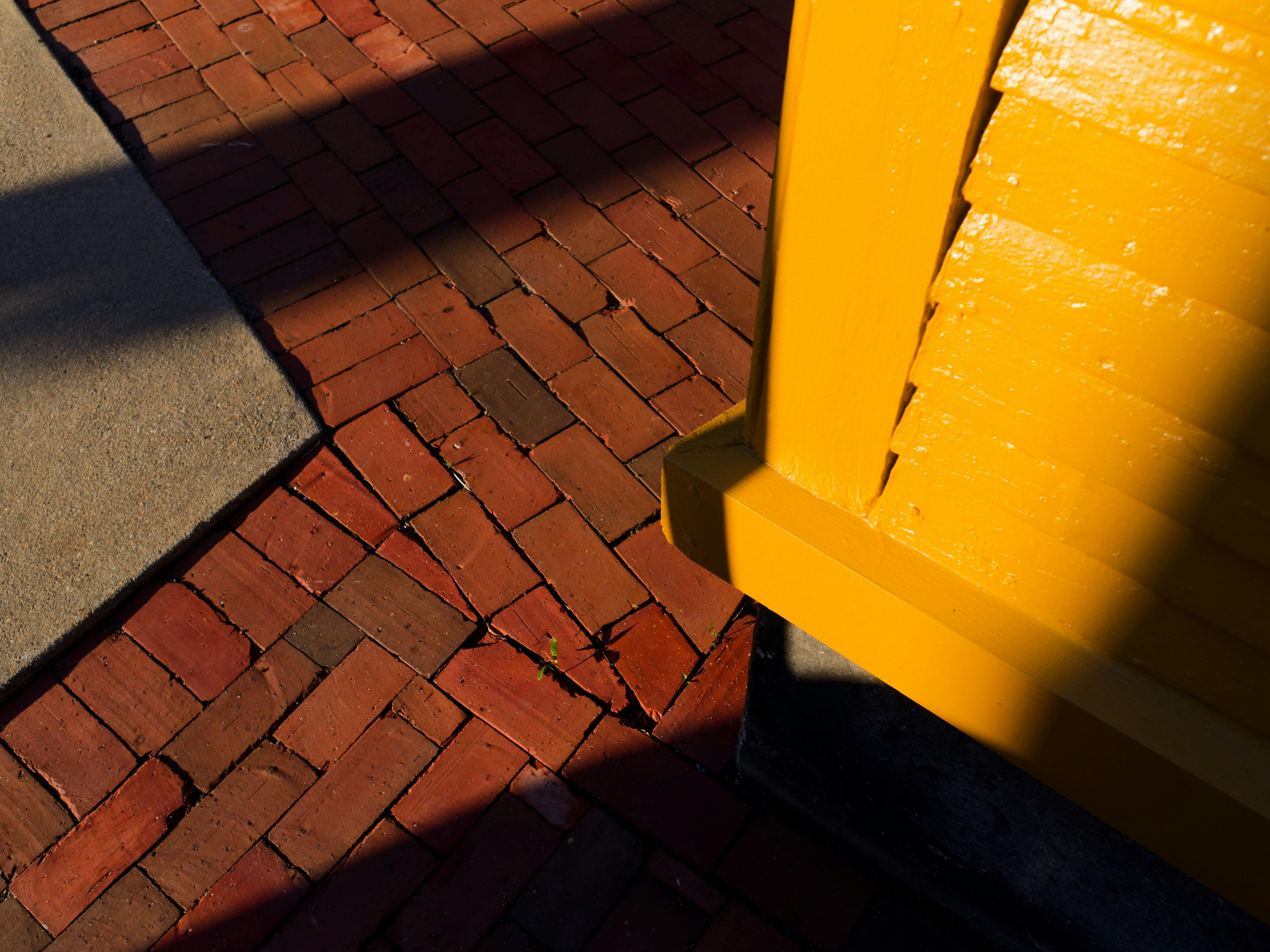 Yellow Accent on Brick Path: A Corner of Sunlit Geometry