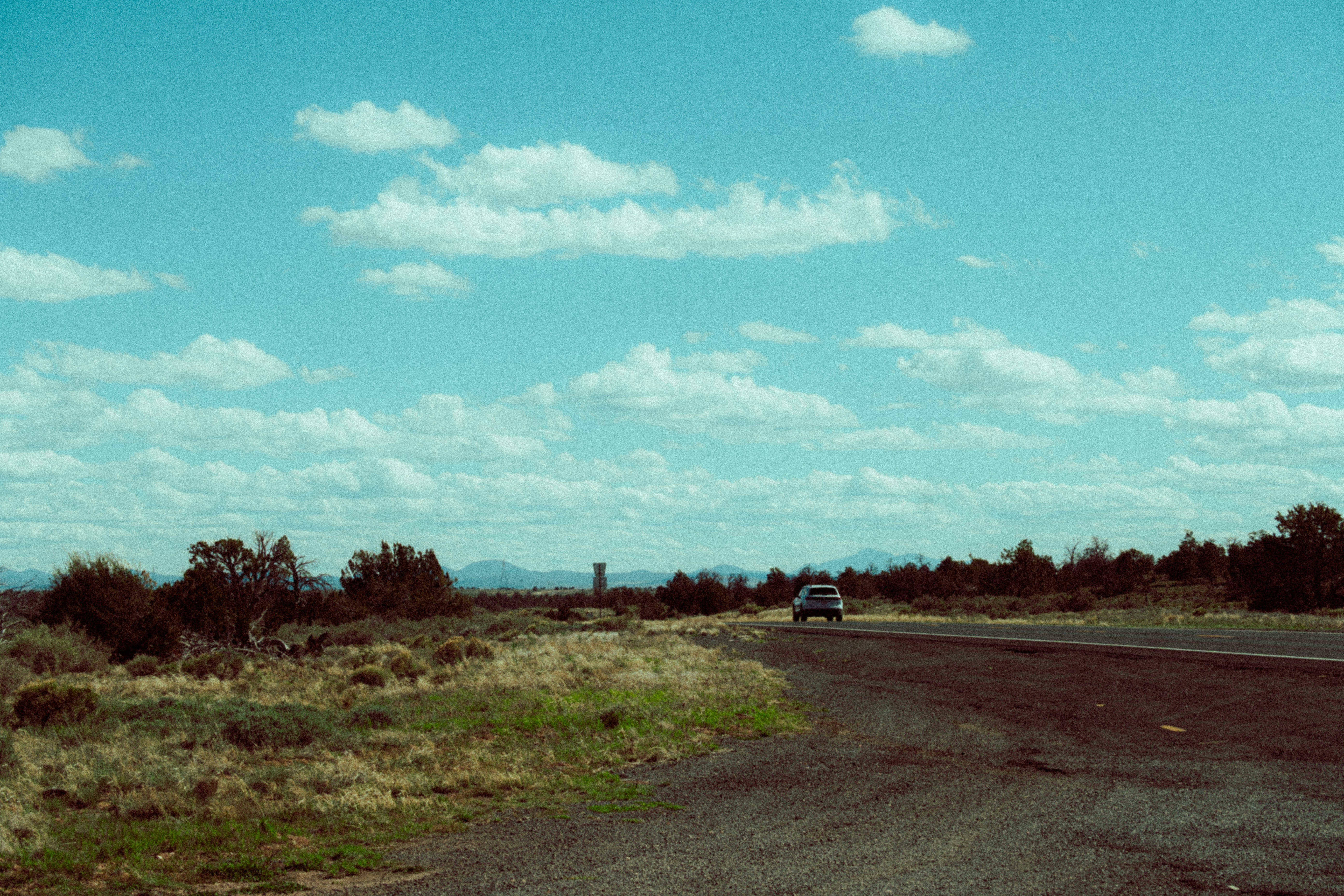 Desert Highway Horizon: A Vanishing Car on a Quiet Road