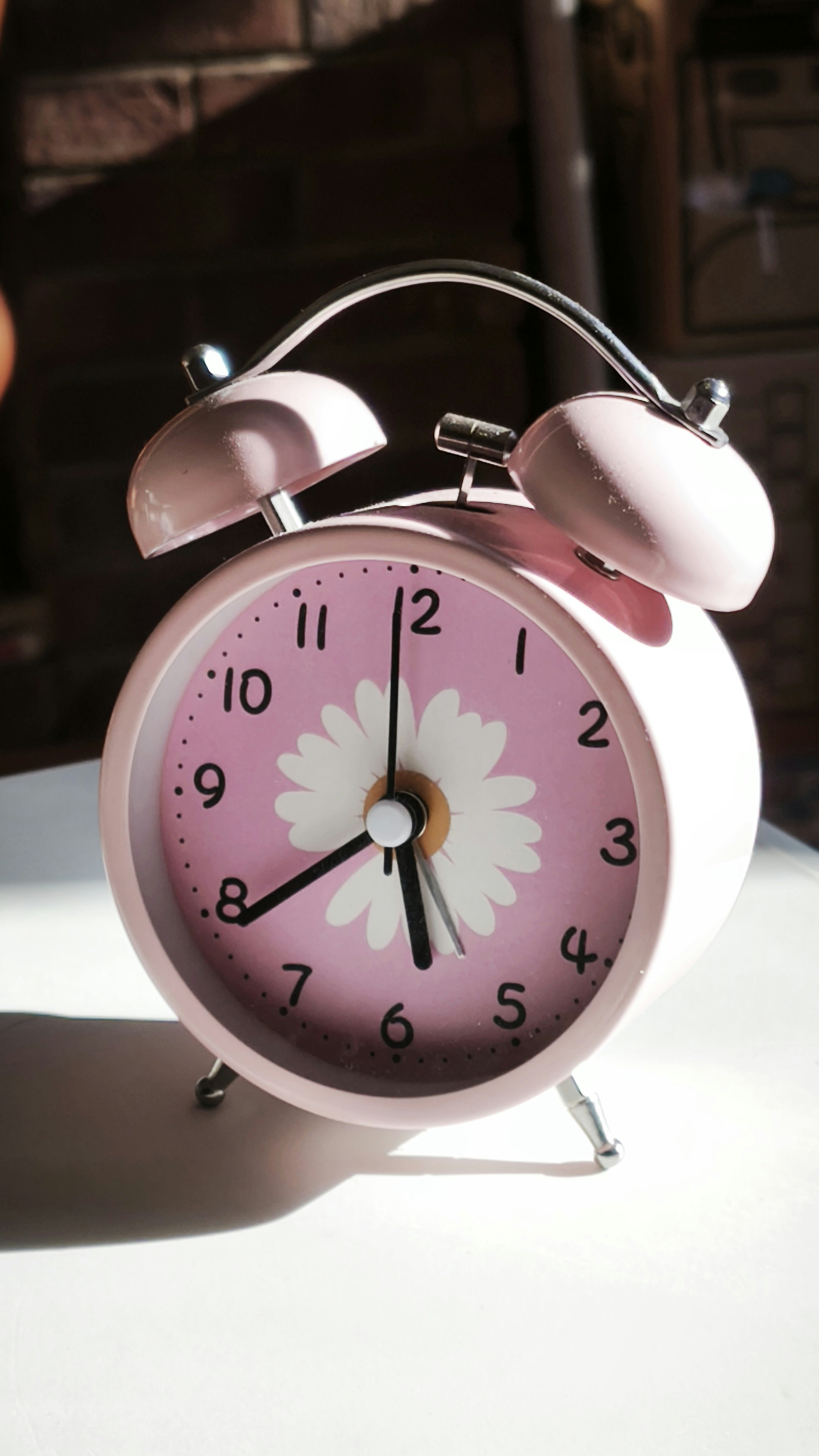 Pink Alarm: A Sunlit Moment with a Daisy-Pattern Clock