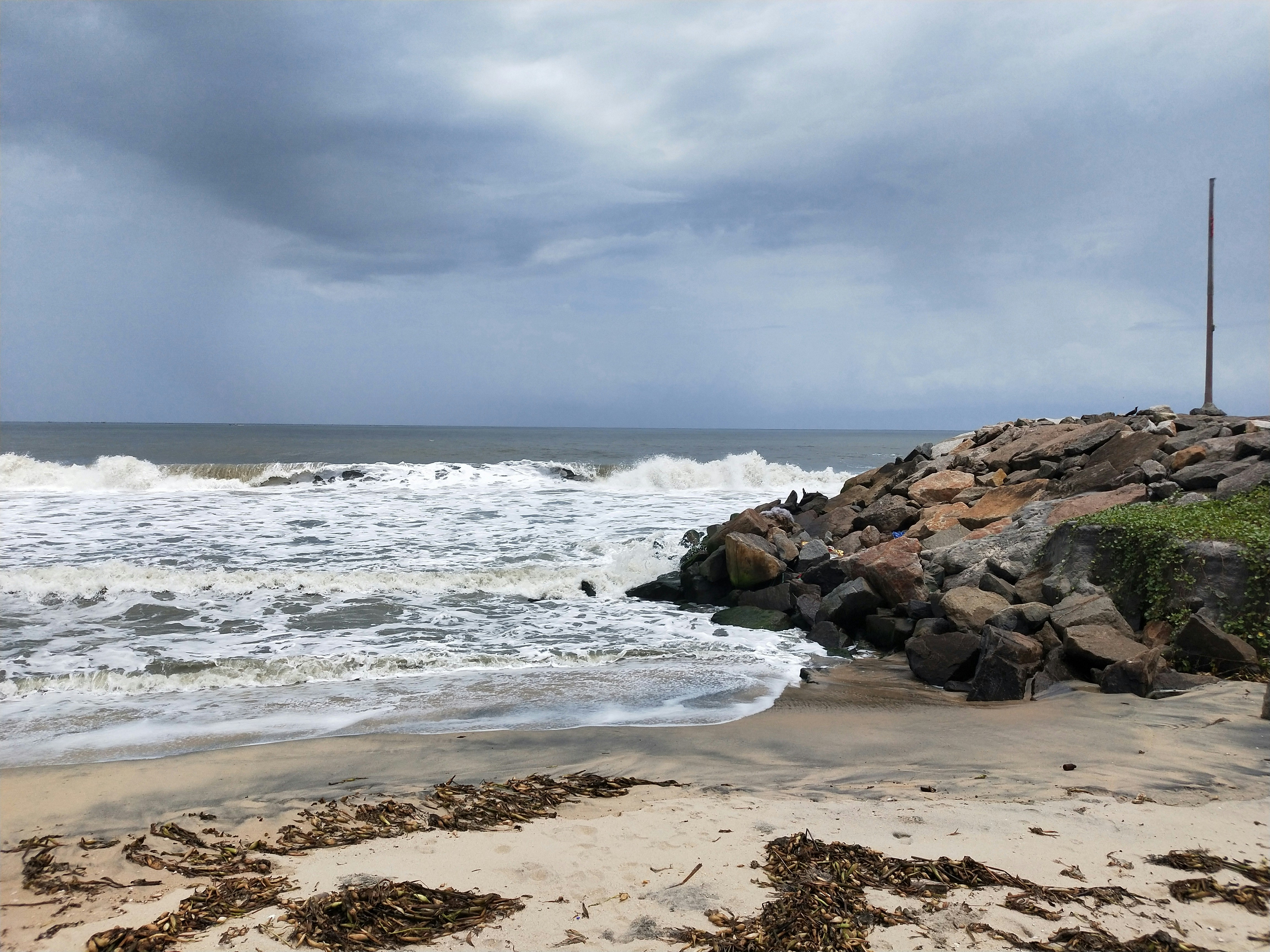 Coastal Confluence: Waves Break Near the Rock Jetty Under a Sage Sky