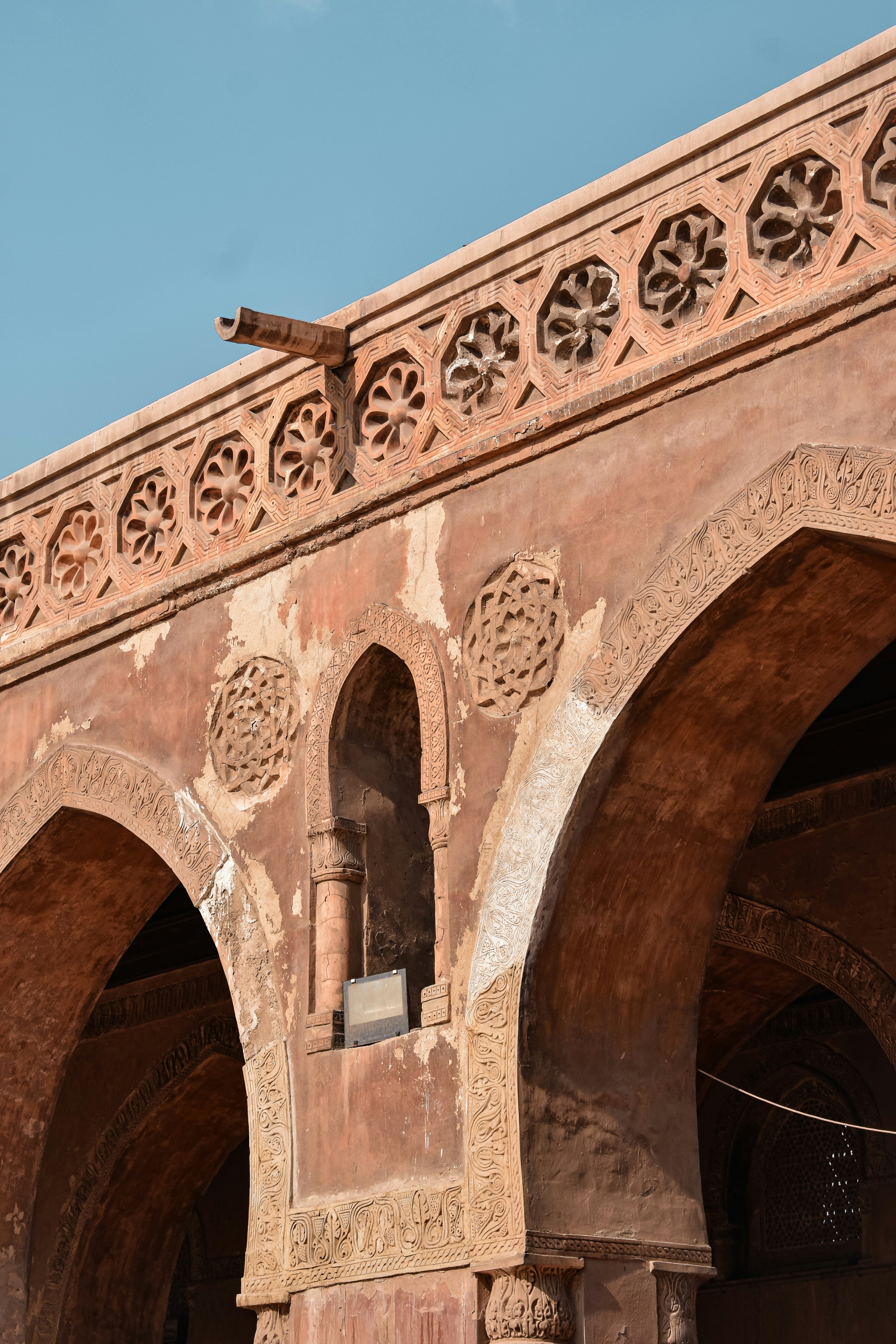 Sunlit Moorish Archways: Ornate Carved Stone and Weathered Facade