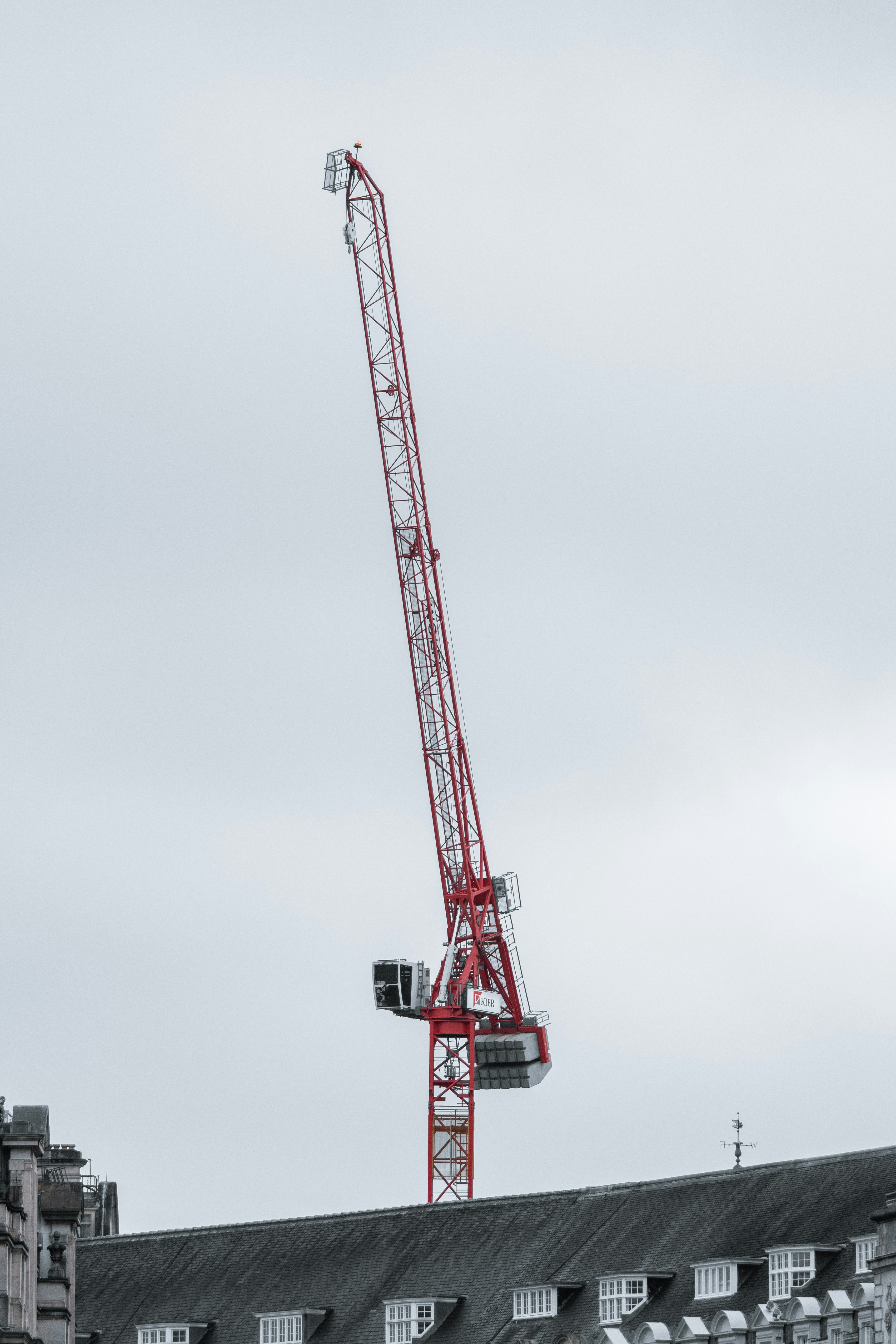 Crane Arced Above the City: A Red Tower Reaches Toward the Clouded Sky