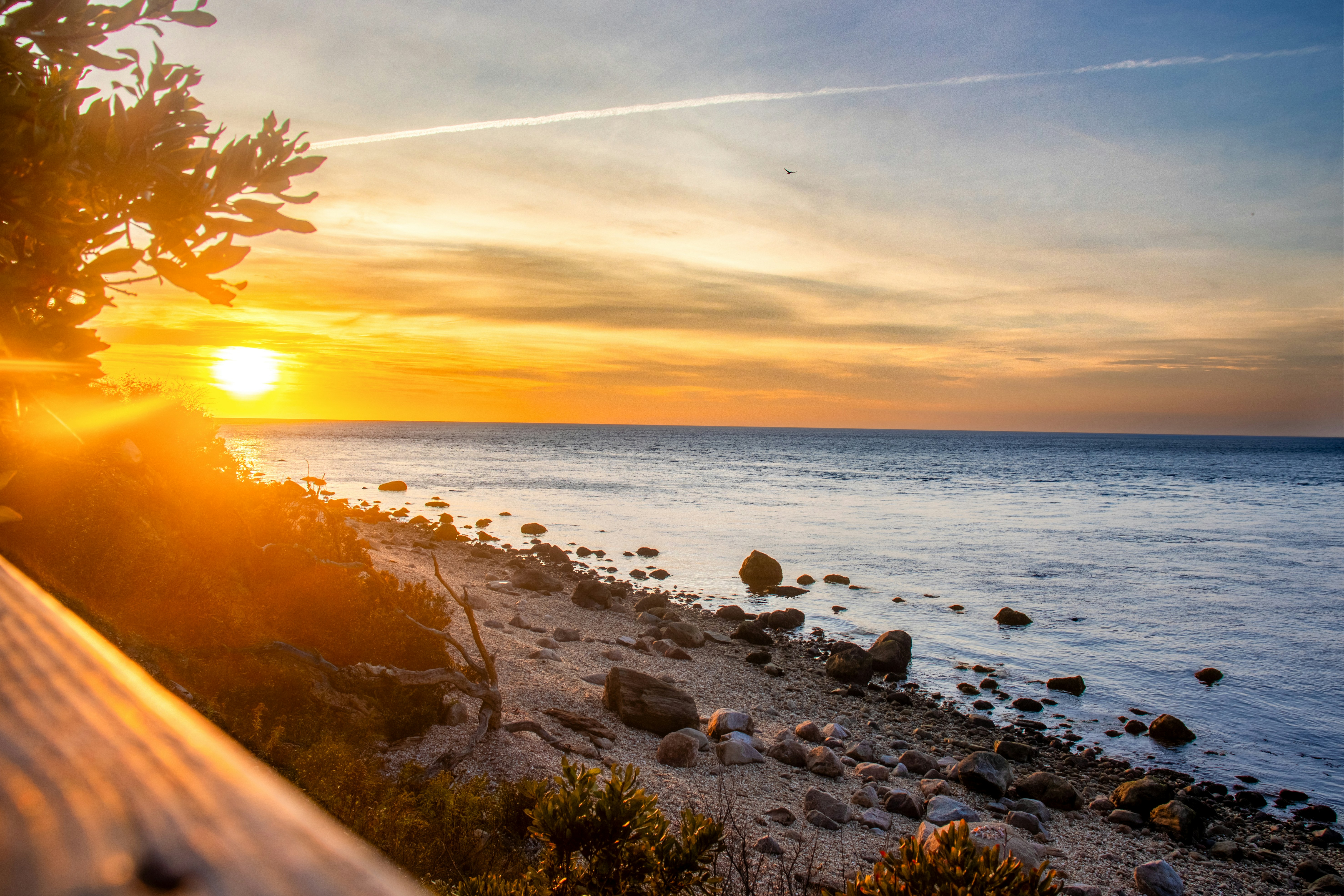 Golden Shoreline at Dusk: Sunlit Rocks and Calm Waves