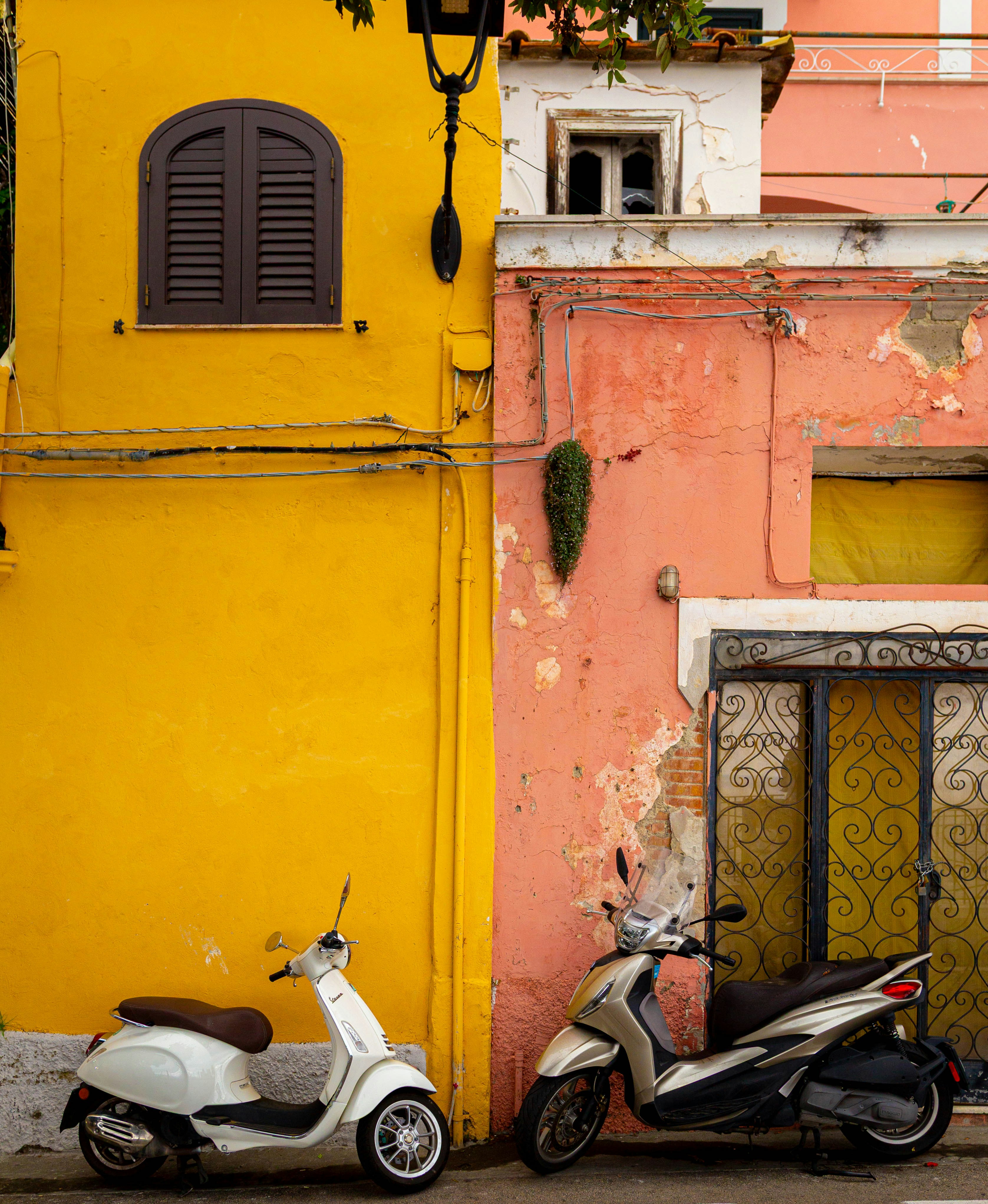 Two Scooters Rest Against a Sunlit Citrus Wall
