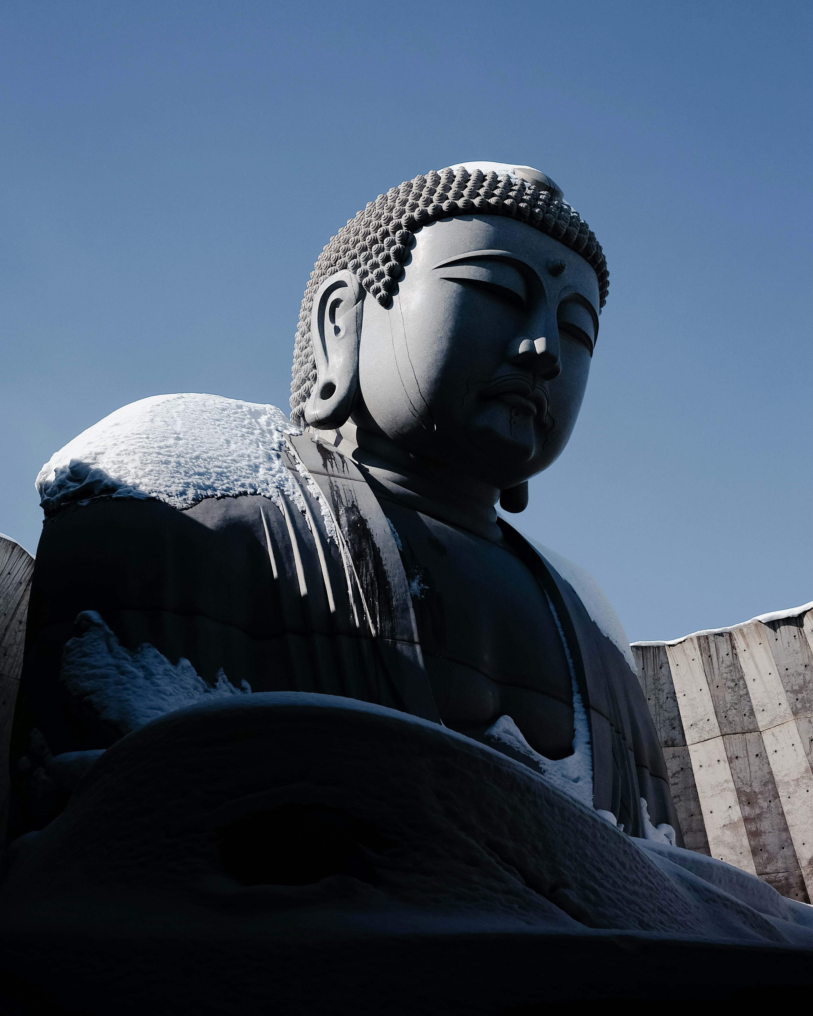 Serene Giant: A snow-kissed Buddha Beneath a Clear Sky