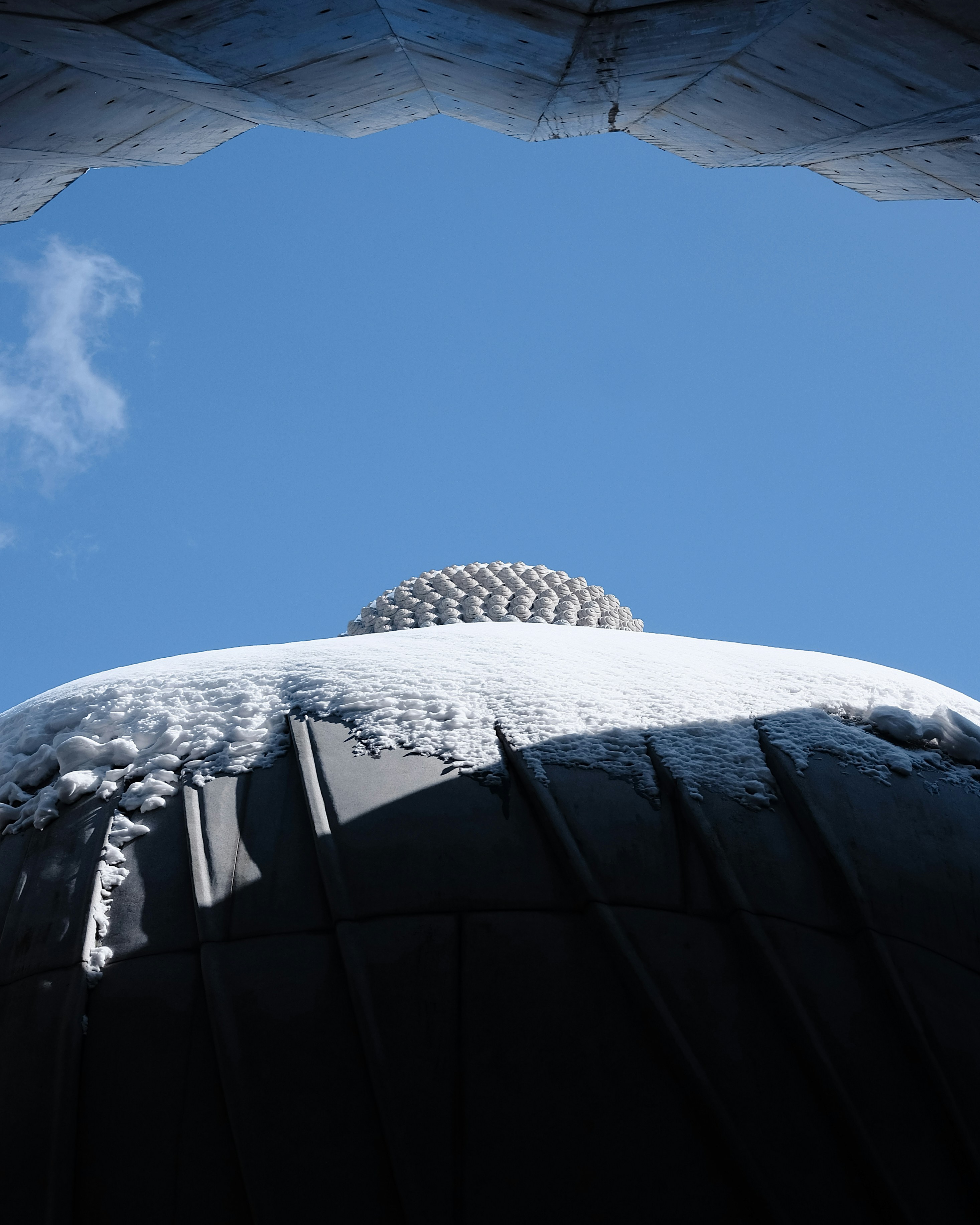 Snow-Crowned Tip of a Tower Beneath a Clear Sky