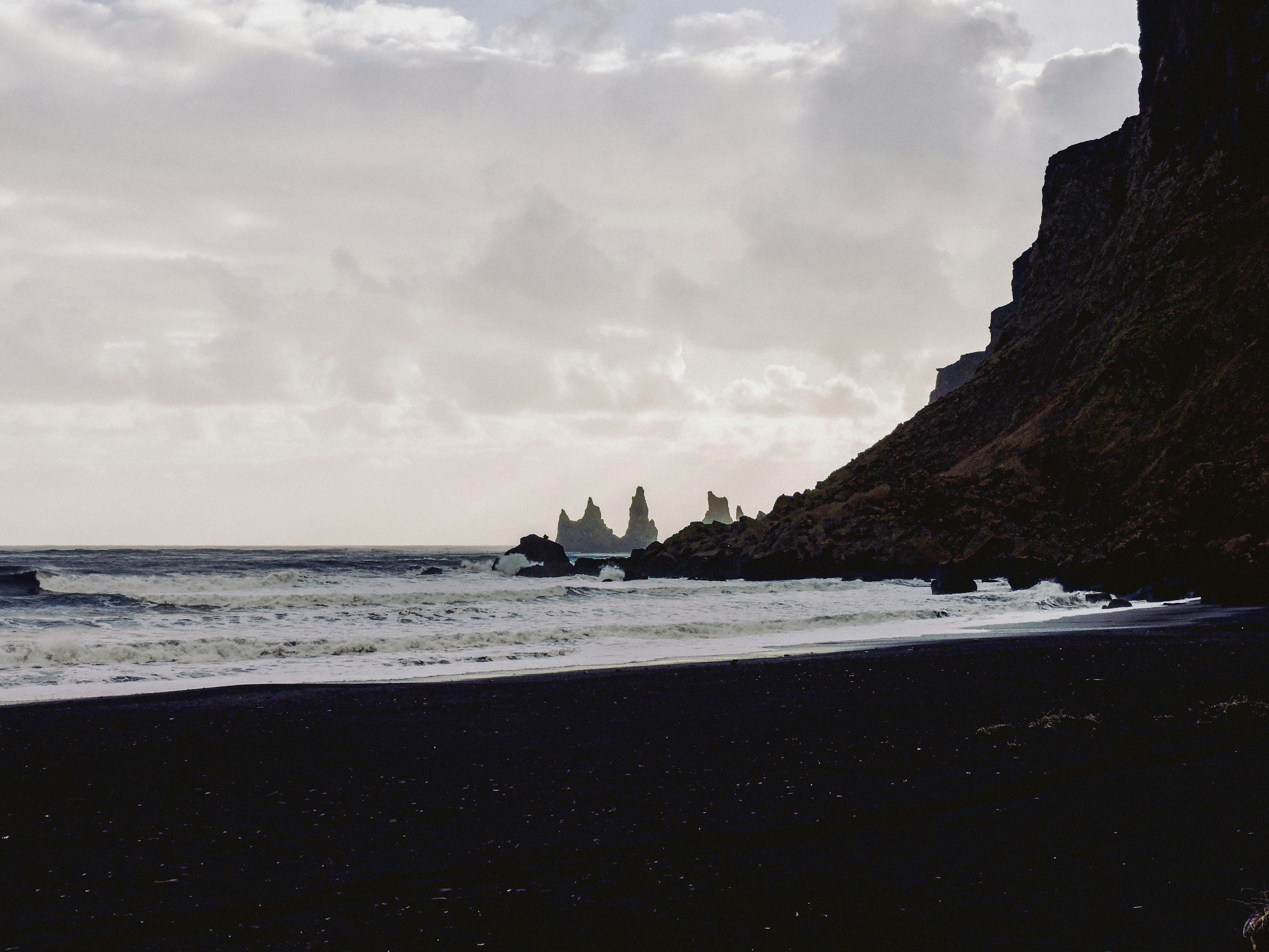 Lone Black Sand Shore Beneath a Stoic Cliff