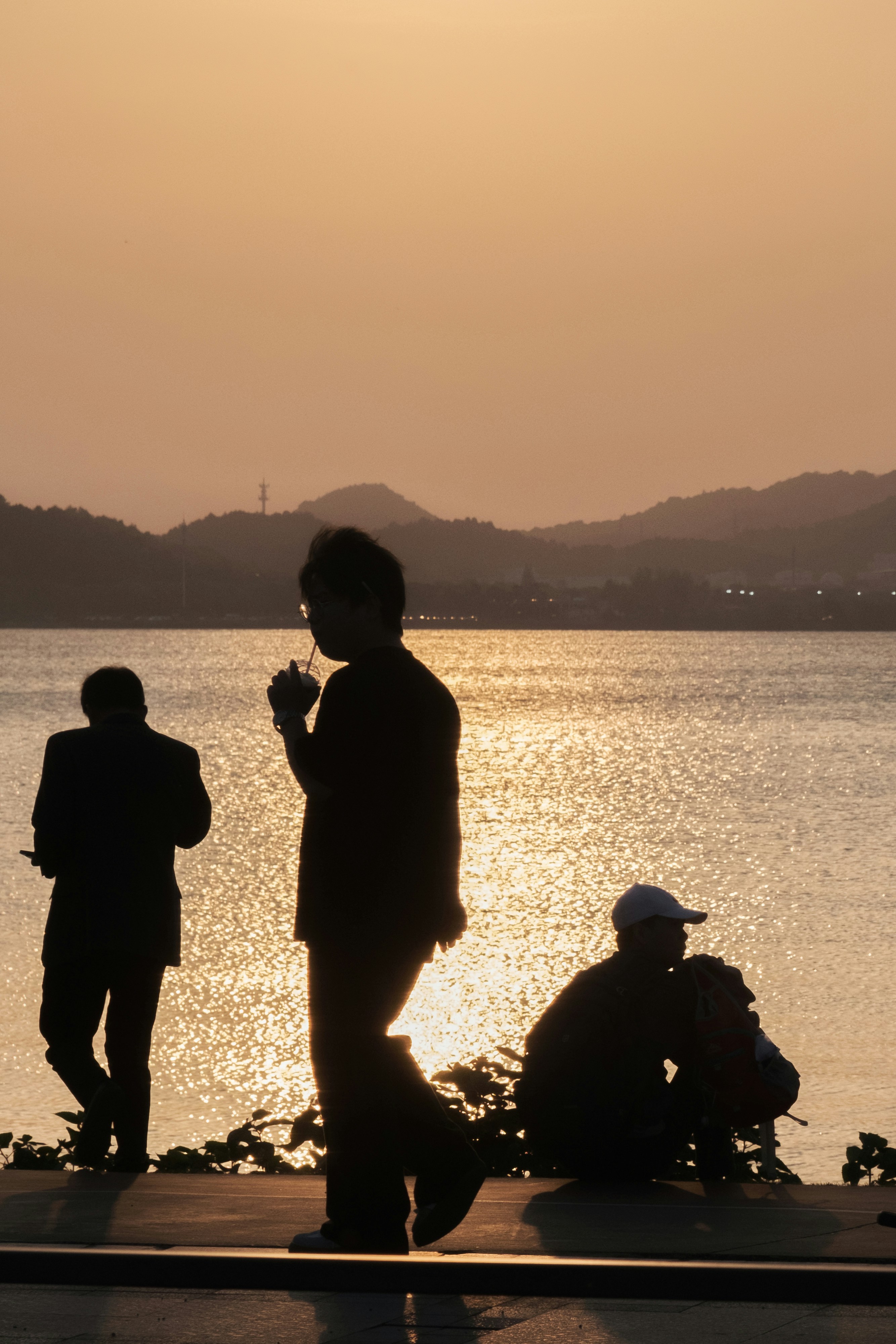 Silhouetted Figures by Golden Water at Dusk