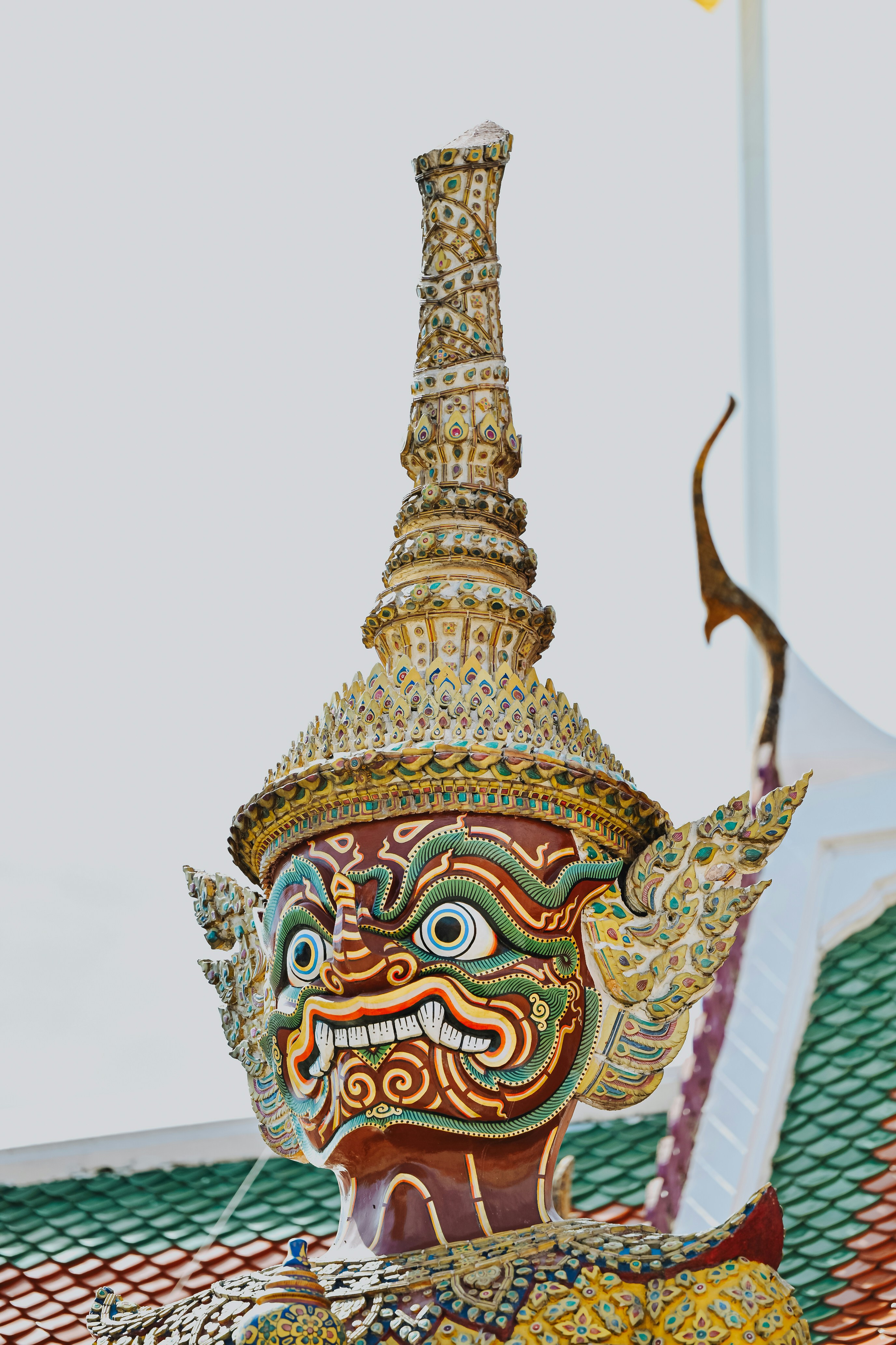 Ornate Guardian: A Colorful Temple Mask Reaches Toward the Sky
