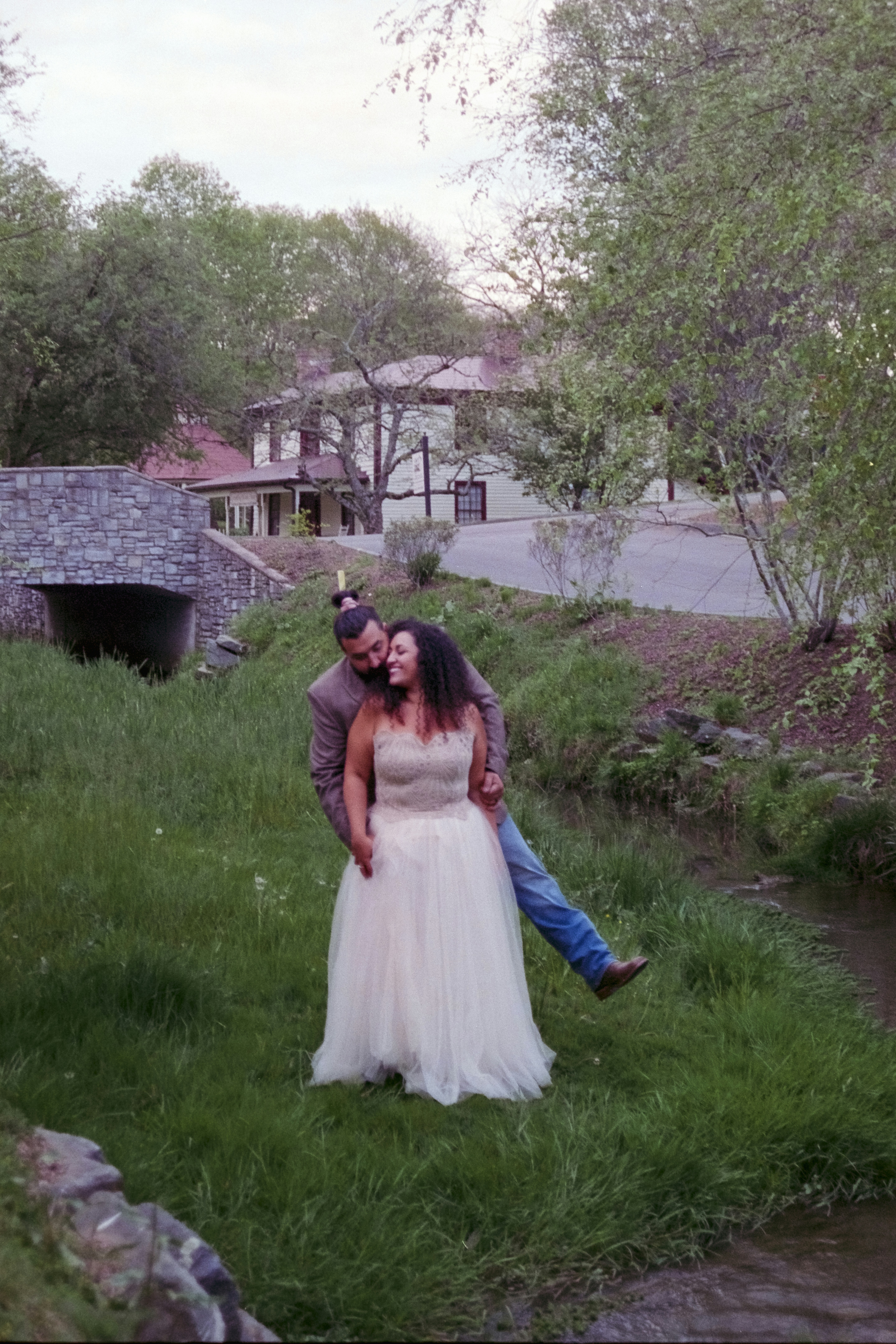 Cozy embrace by the creek: a couple on a grassy bank