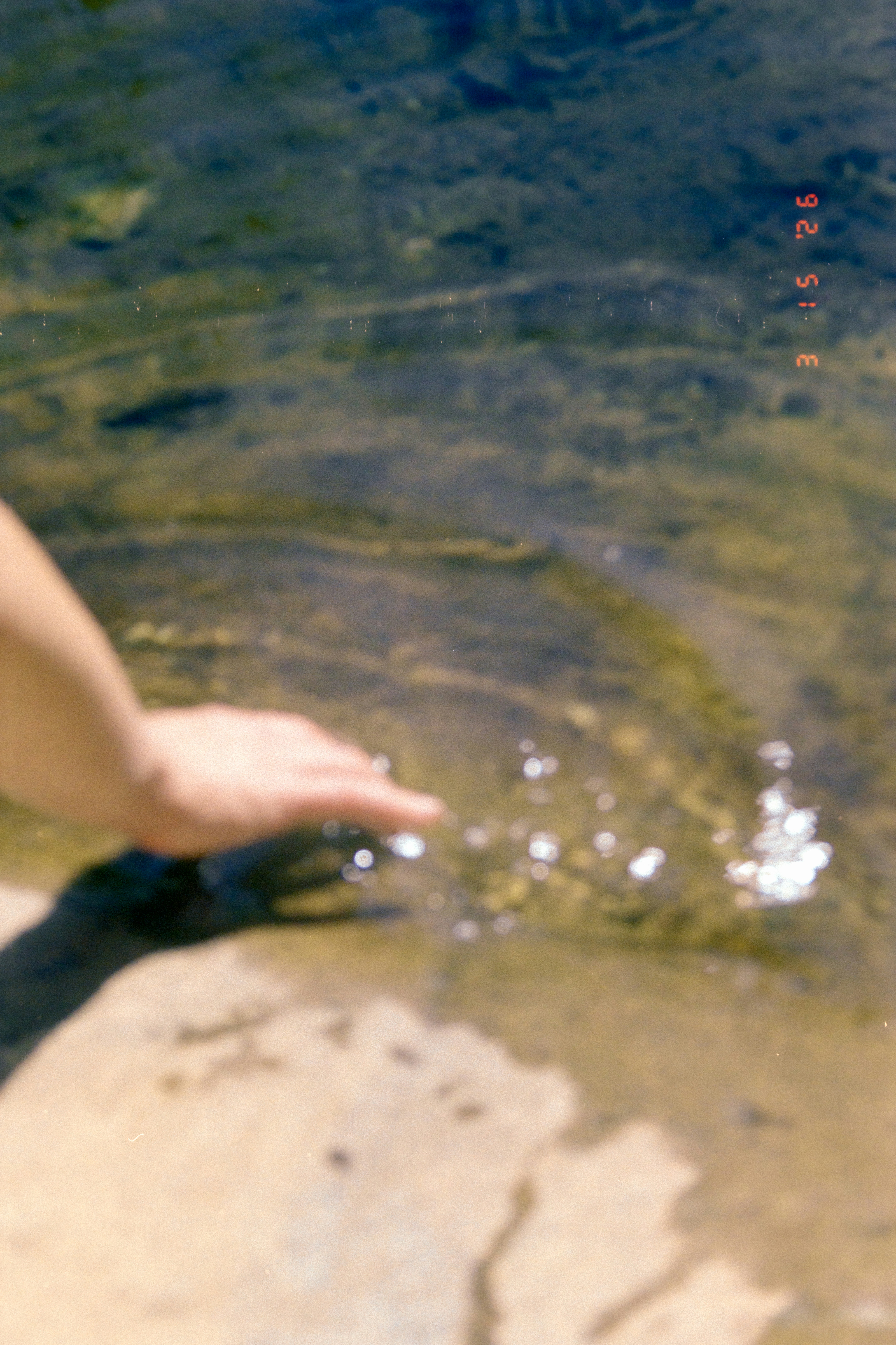 Blurred Reach: A Barefoot Dip by Shimmering River Stones