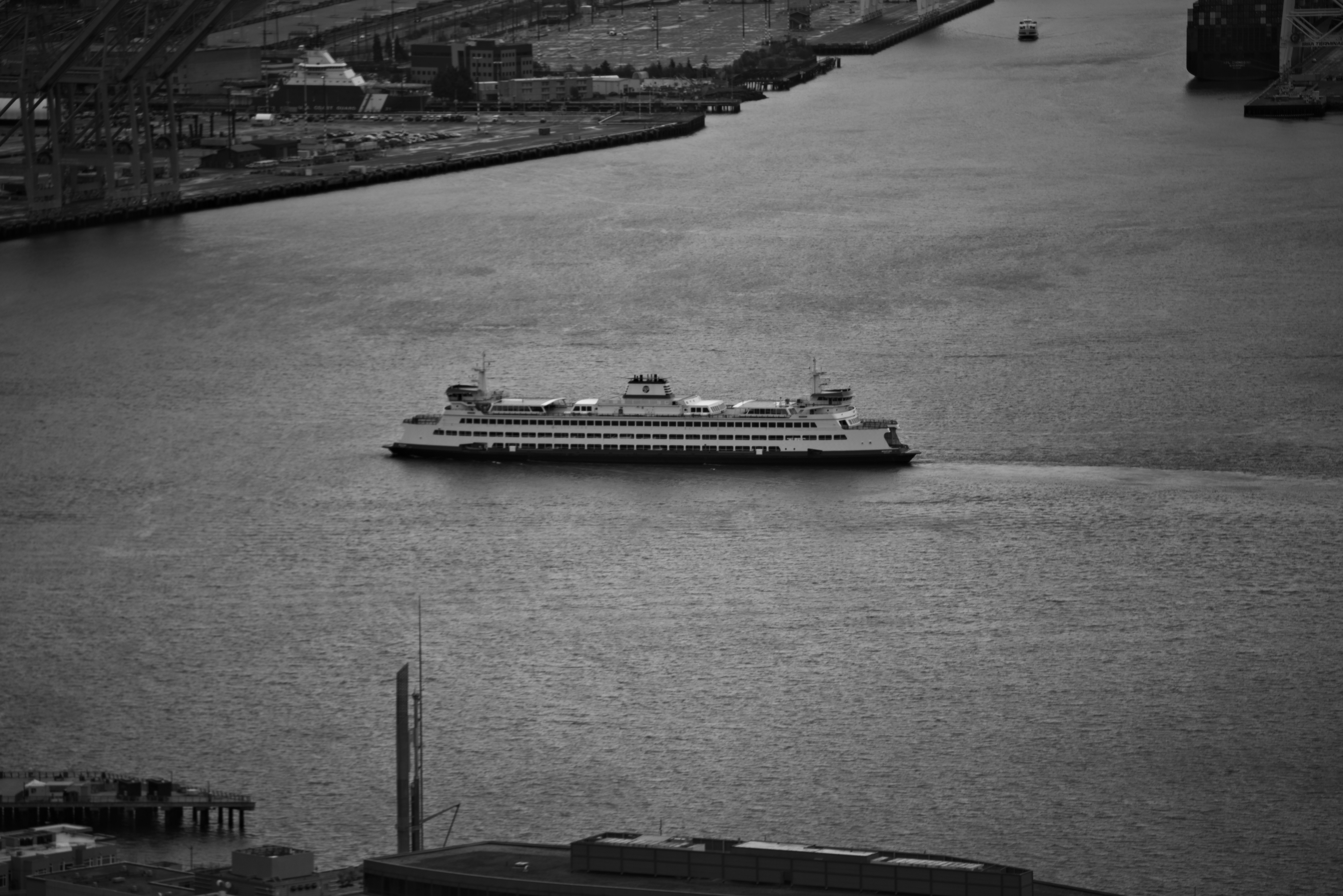 Bright ferry carving a quiet arc through a gray harbor