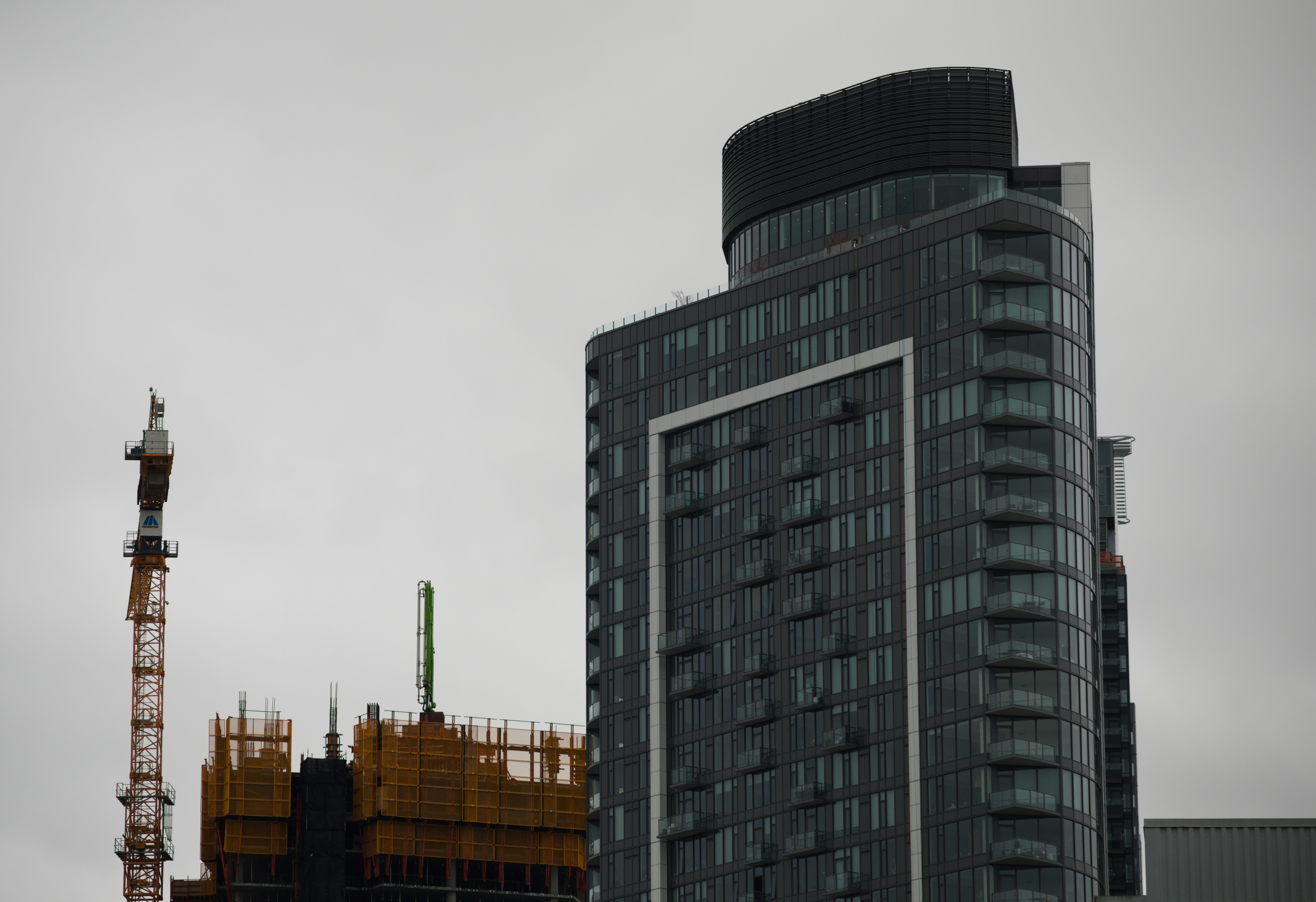 Skyscraper Under Overcast Sky: Glass and Crane Confluence