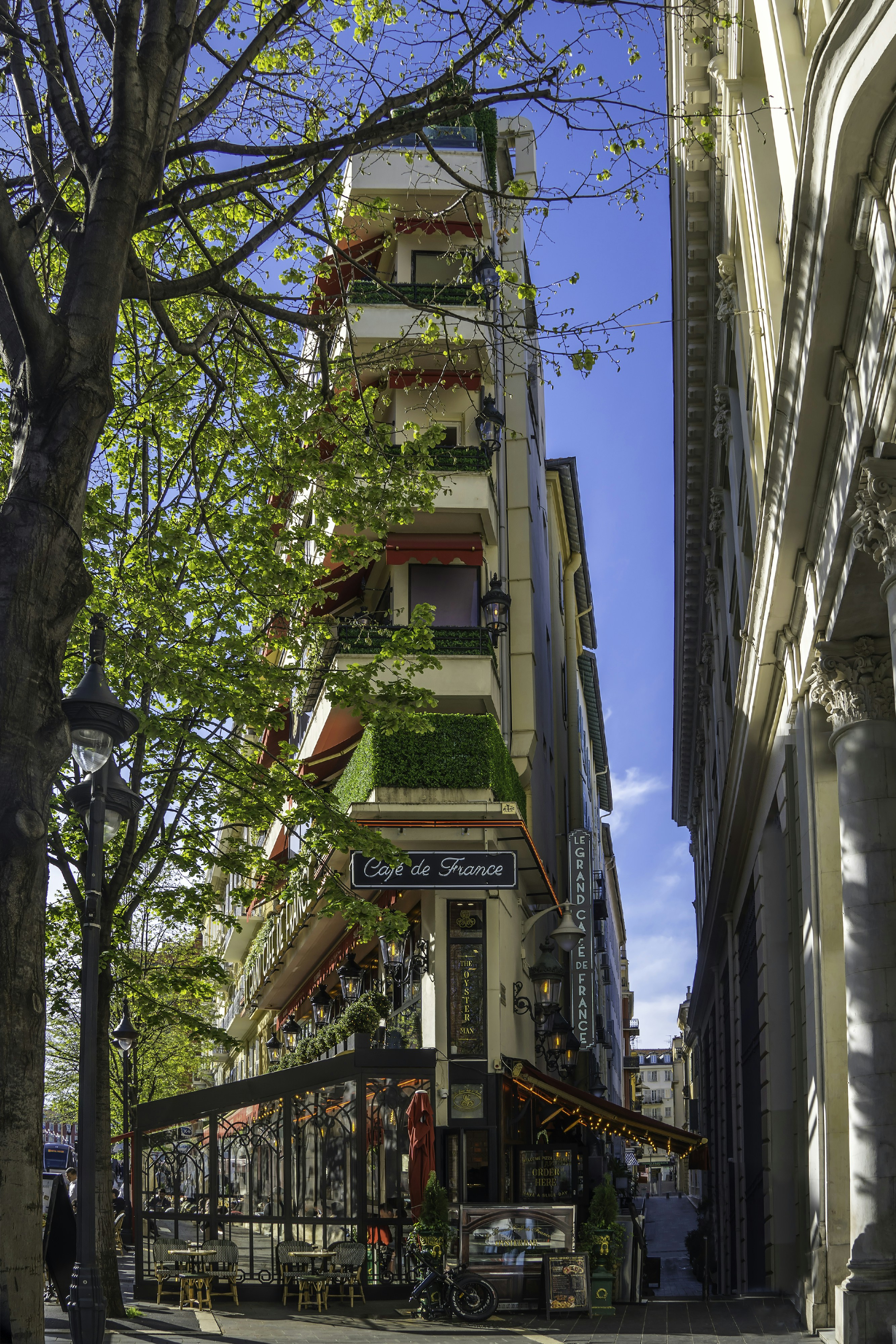Balconies in Bloom: A Sunlit Parisian Café Tucked Between Architecture
