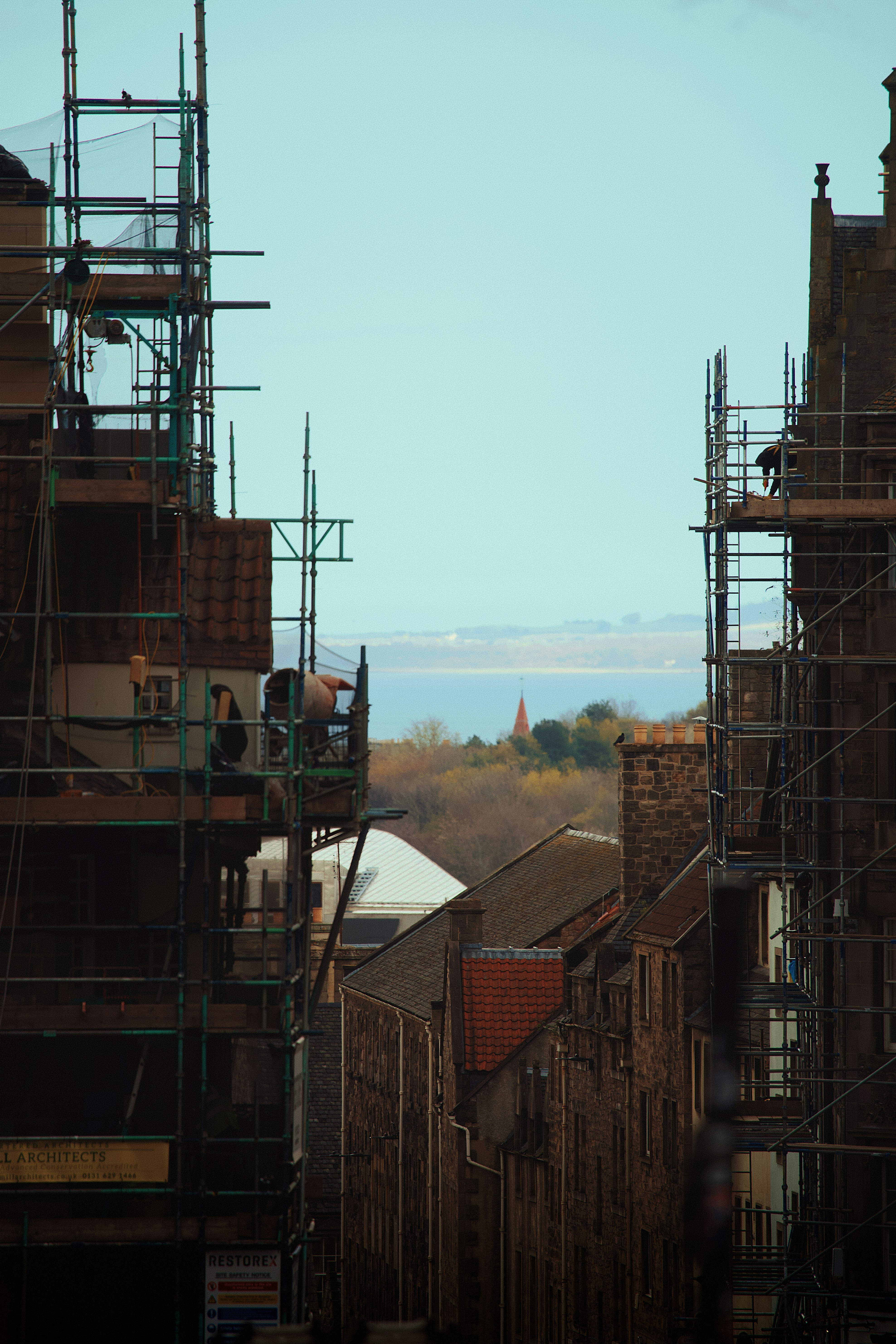 Between the Towers: A Narrow Street Framed by scaffolding toward a distant church spire