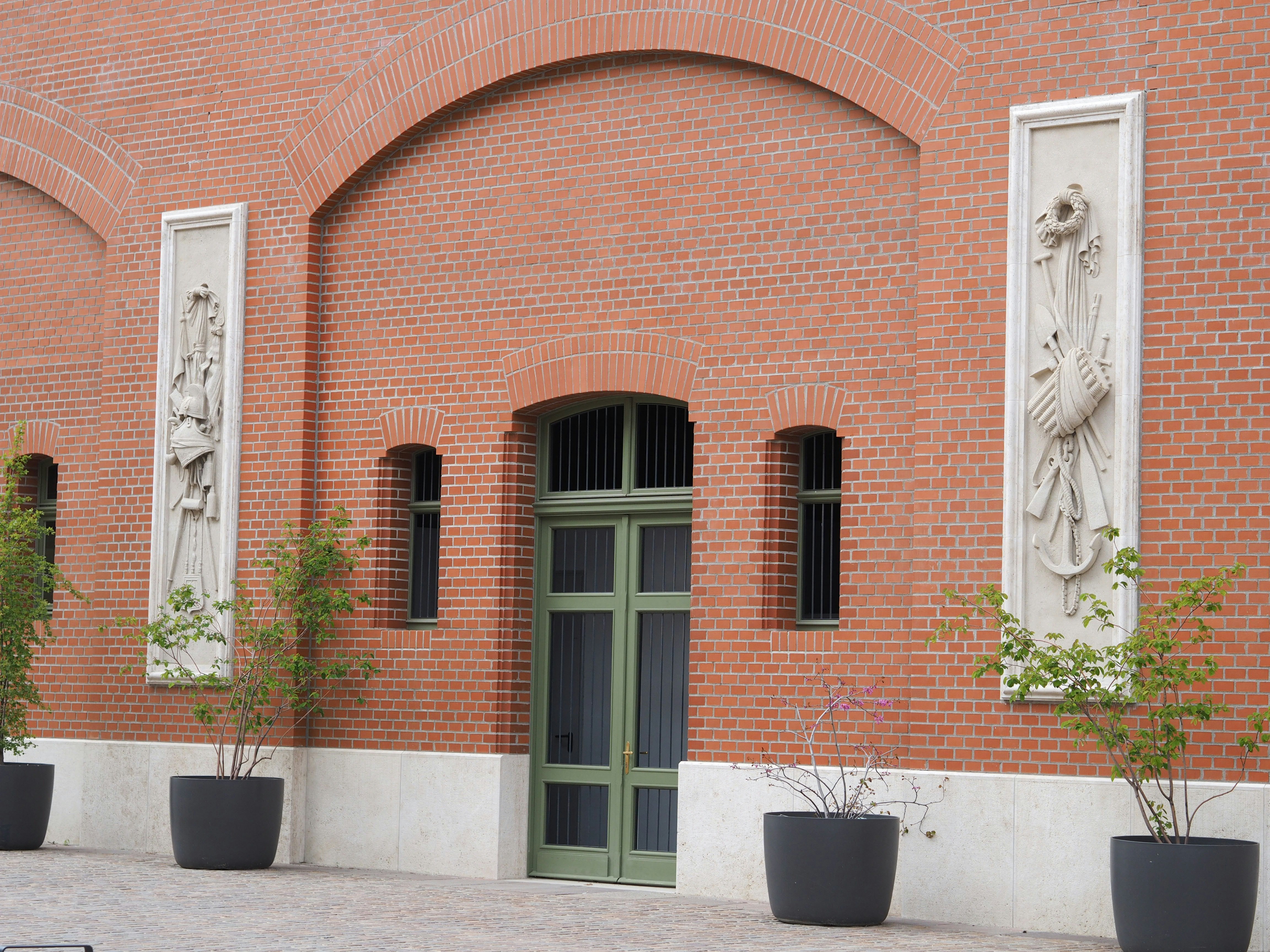 Green-arched doorway under a brick facade with sculpted vertical reliefs
