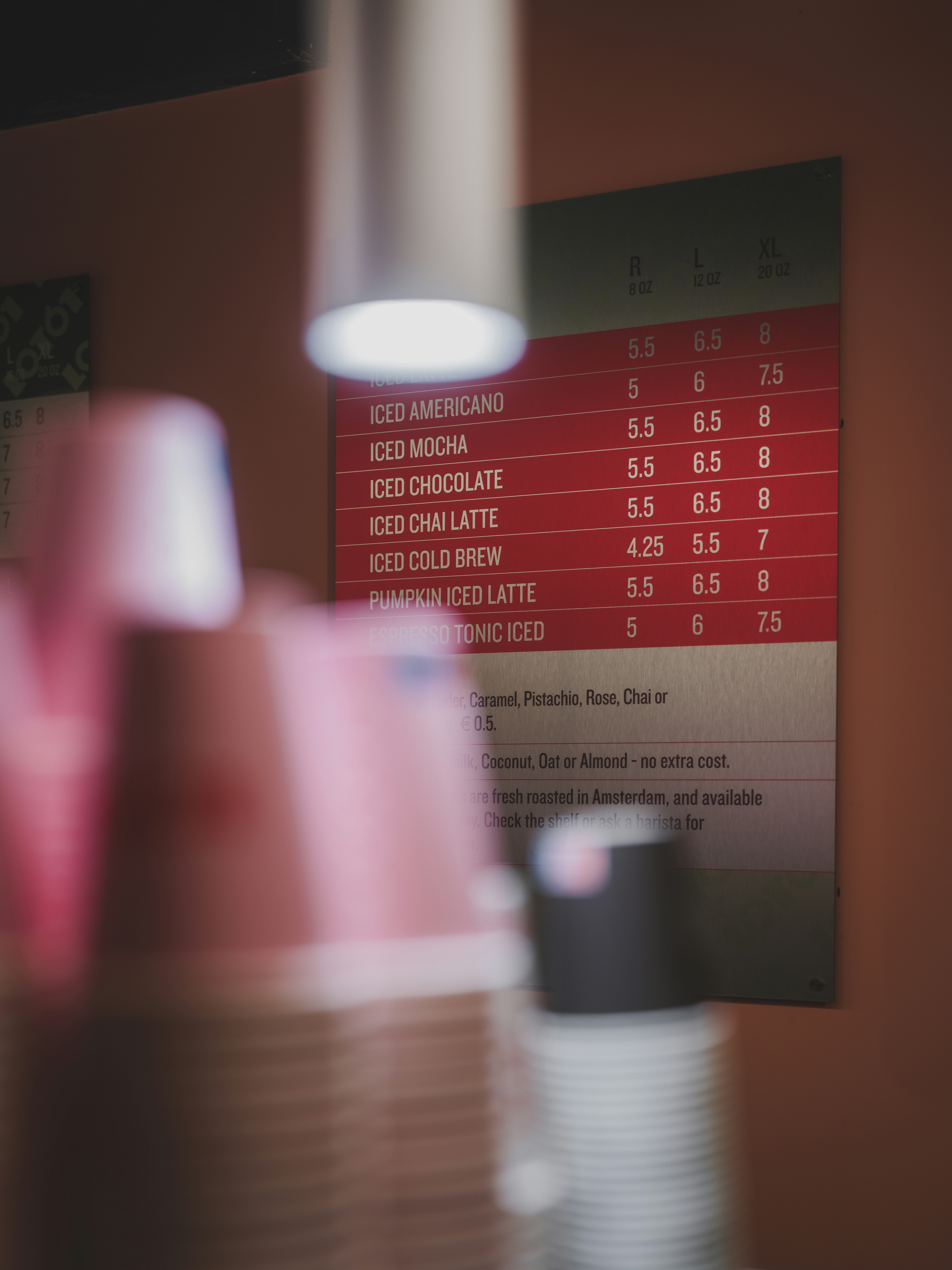 Blurred Cup Tower Over a Menu Board: Neon Warmth and Soft Focus