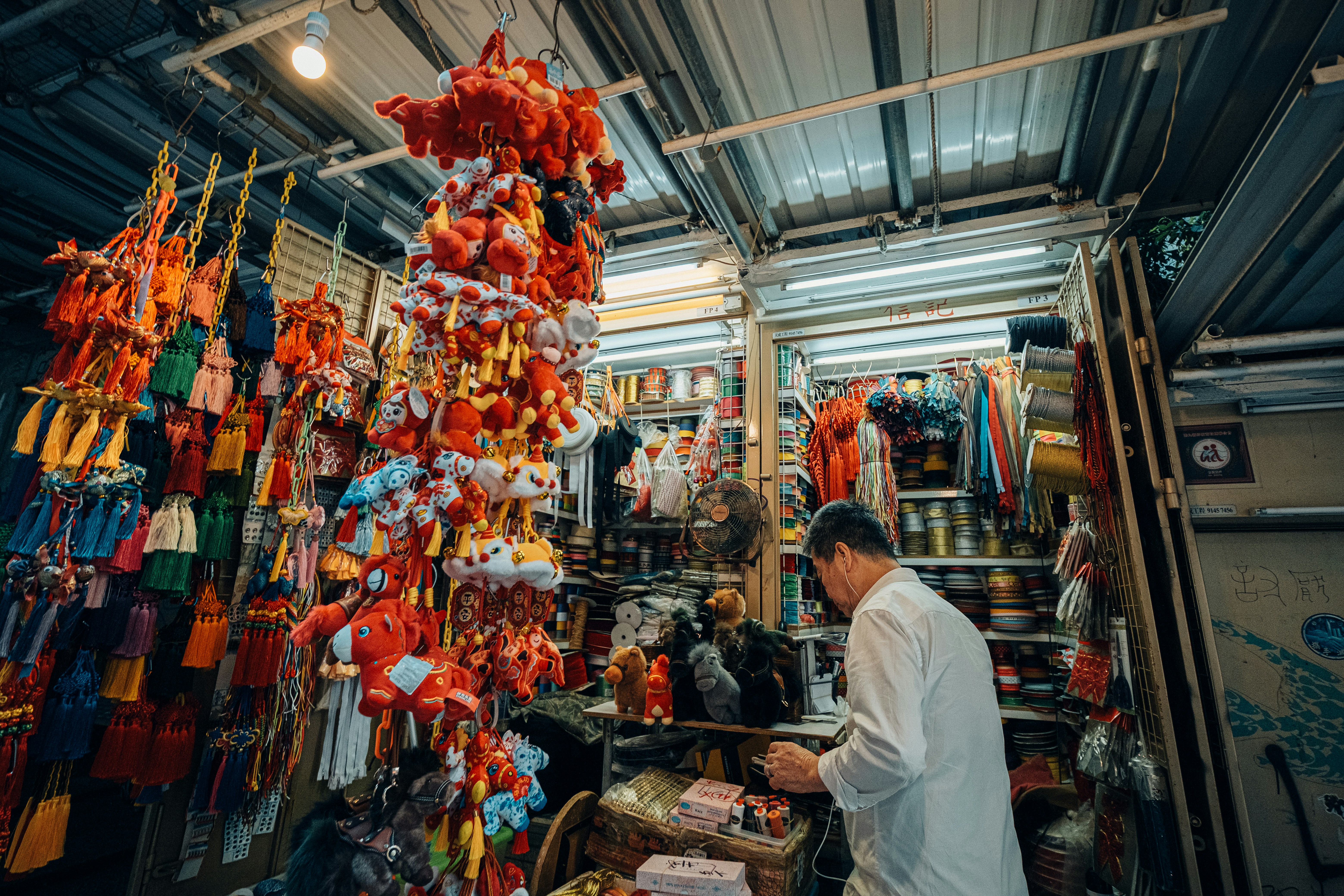 Colorful Toy Bazaar Stall with a Man Inspecting Charms and Plushes
