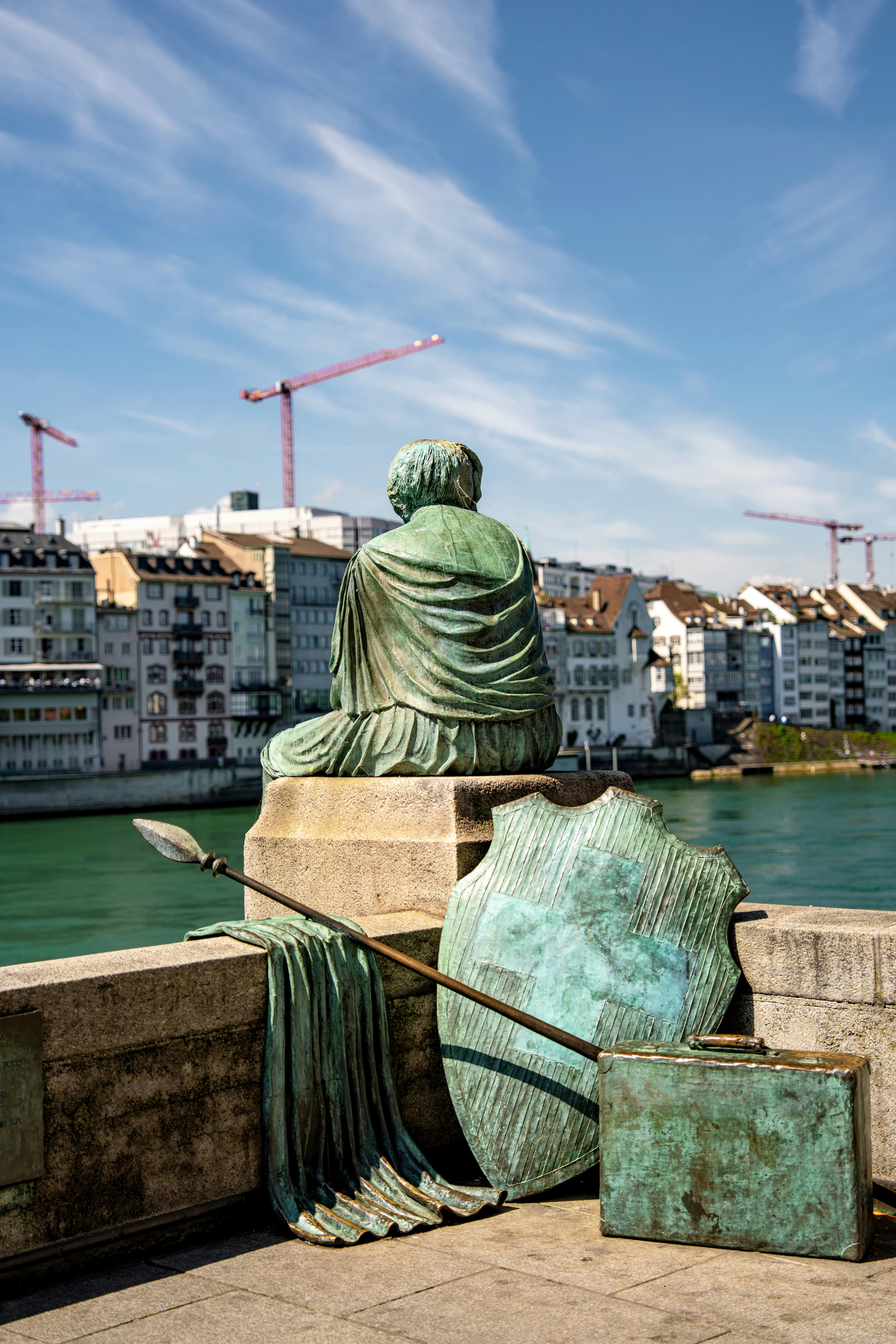 Beside the River: A Quiet Cast of Bronze in Front of a City of Cranes