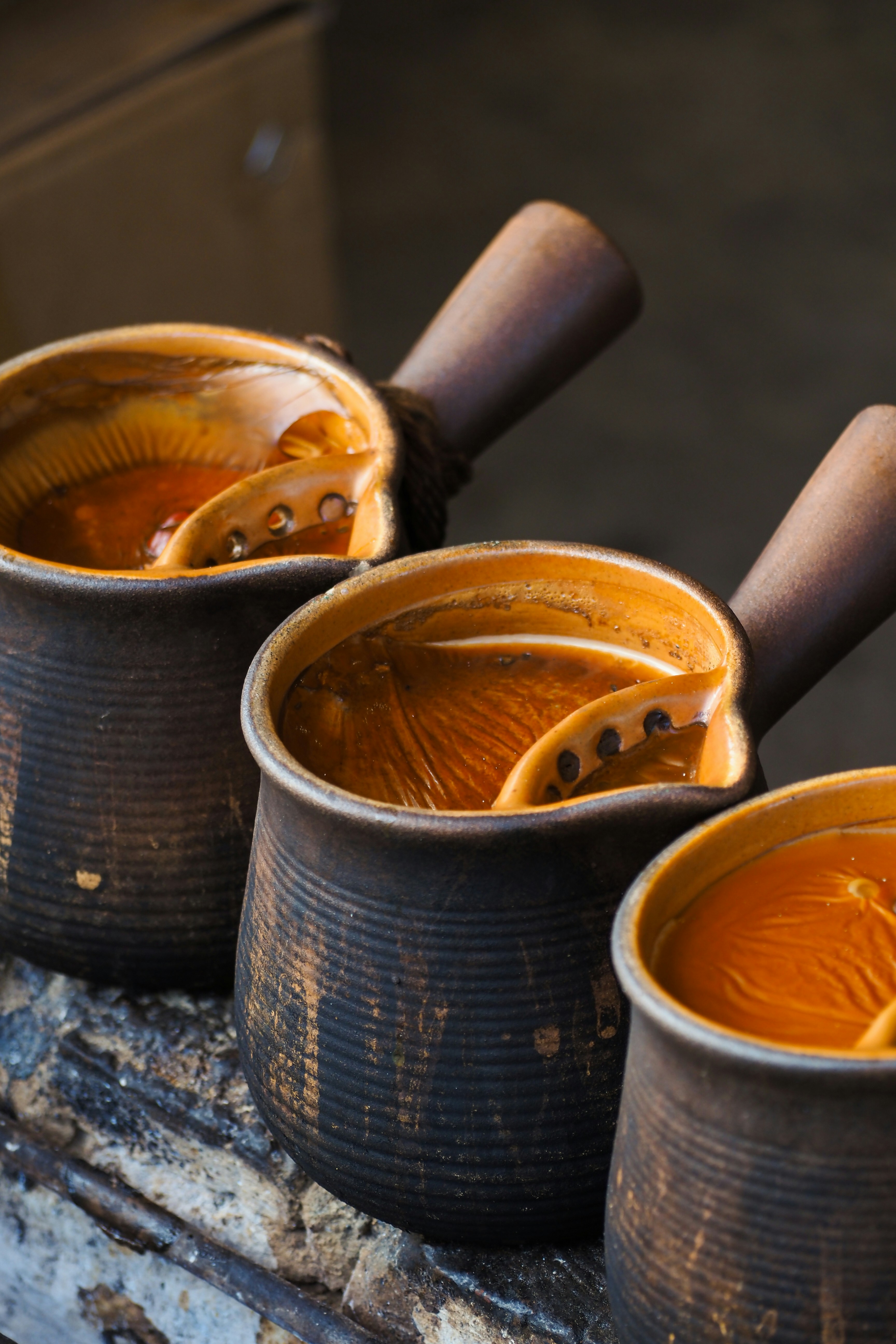 Three Copper Pots: A Row of Glazed Coffers on a Textured Worktop